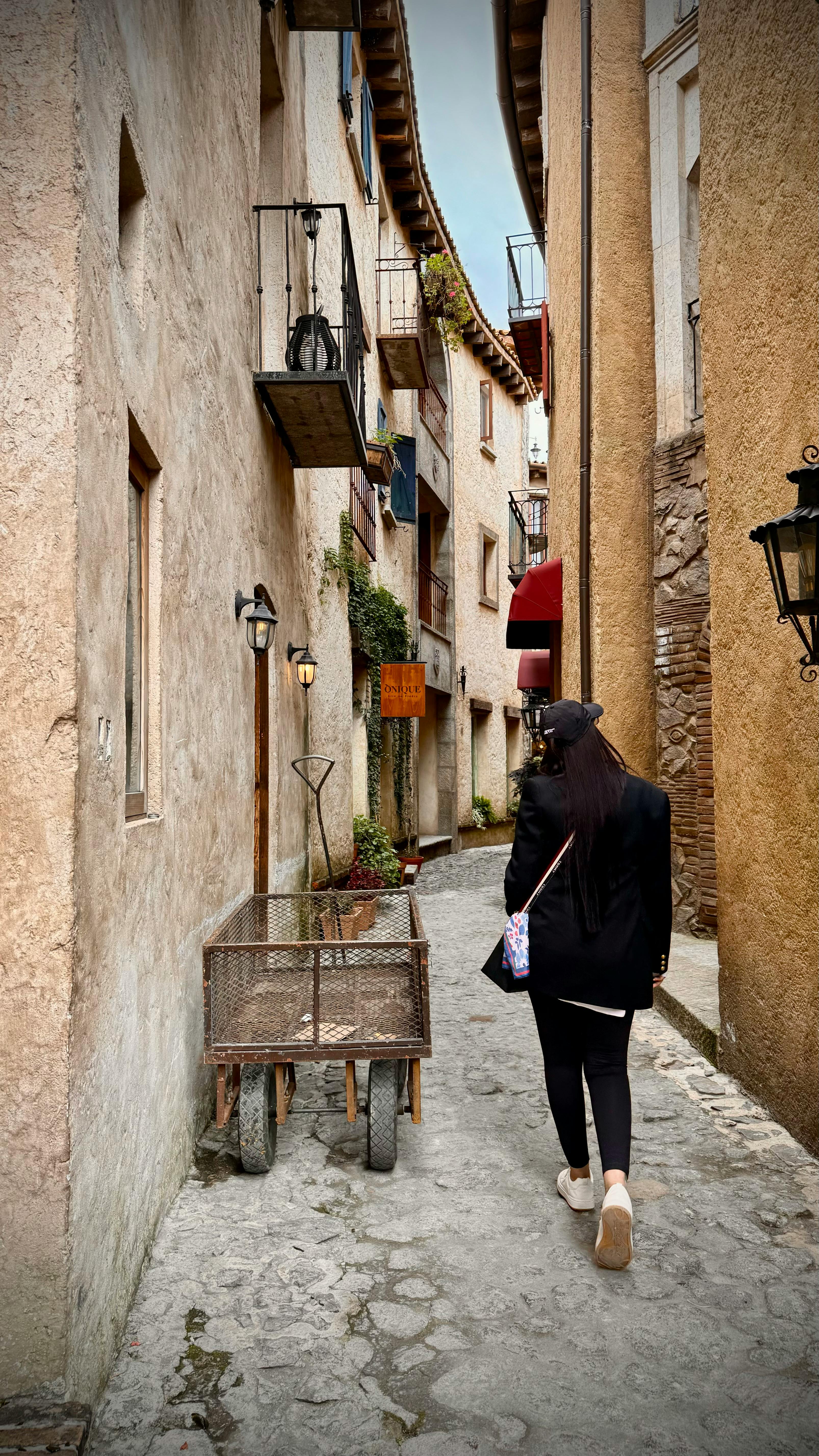 Woman Strolling Through Narrow European Alley · Free Stock Photo
