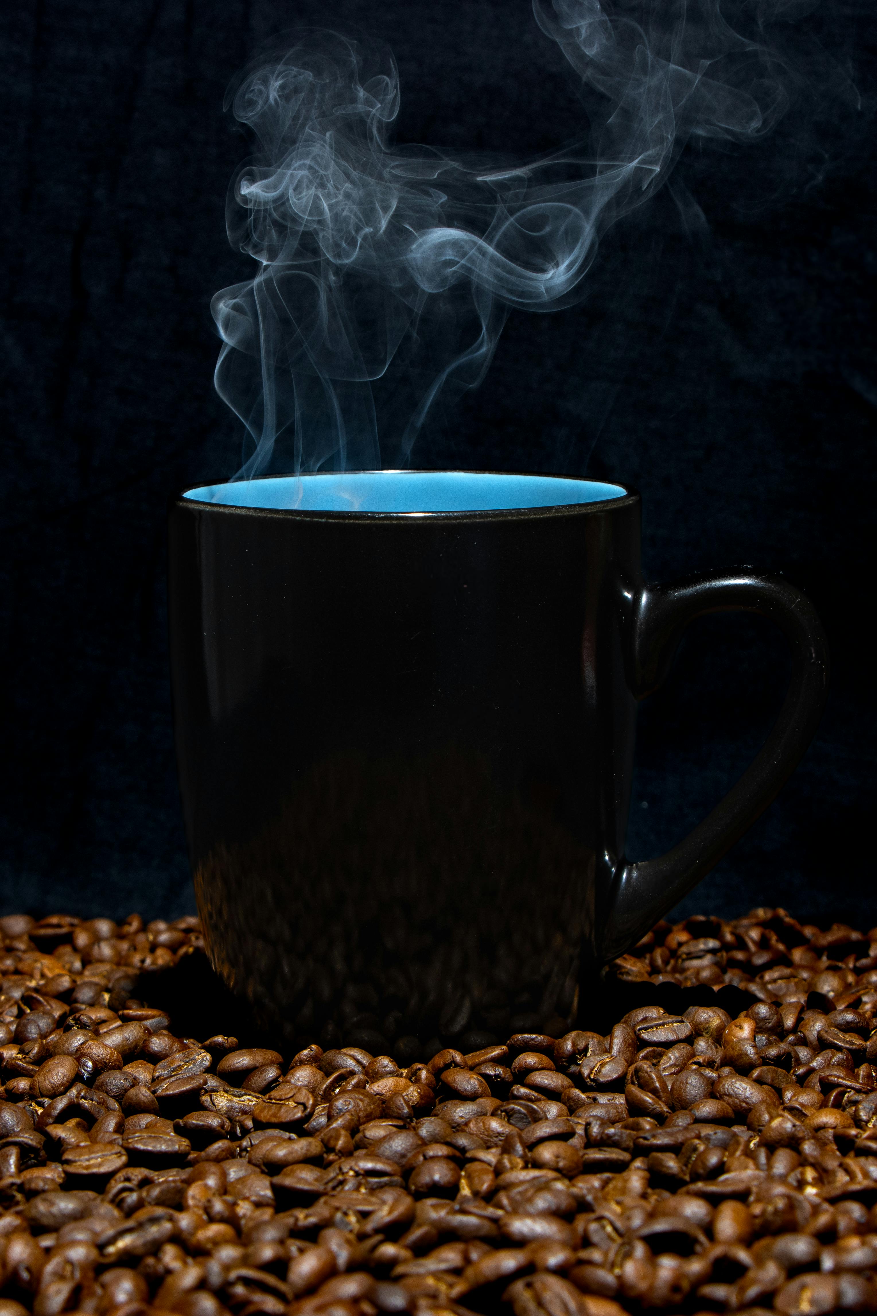 Steaming Coffee Mug Surrounded by Coffee Beans · Free Stock Photo