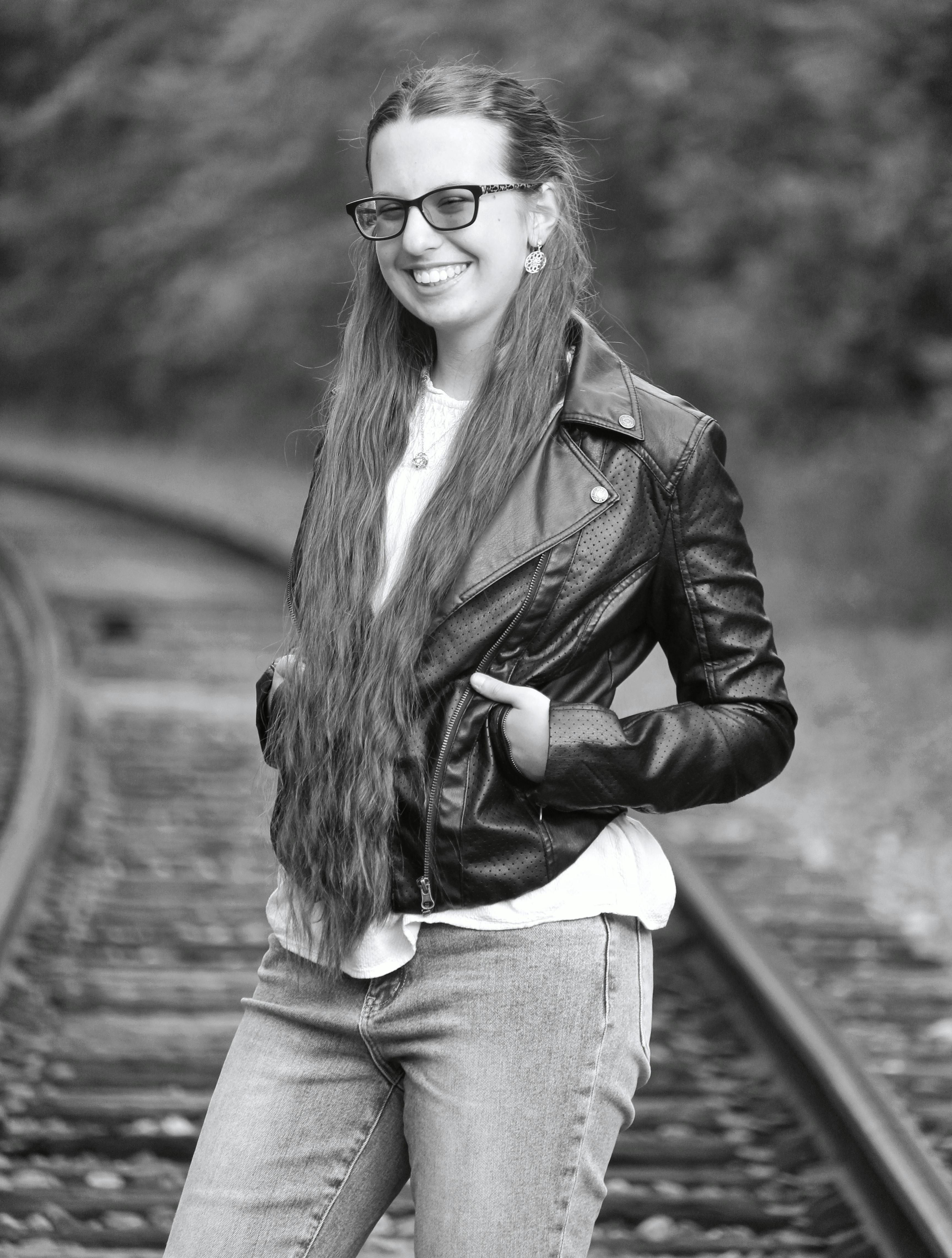 Black and White Portrait of Smiling Woman on Train Tracks · Free Stock Photo