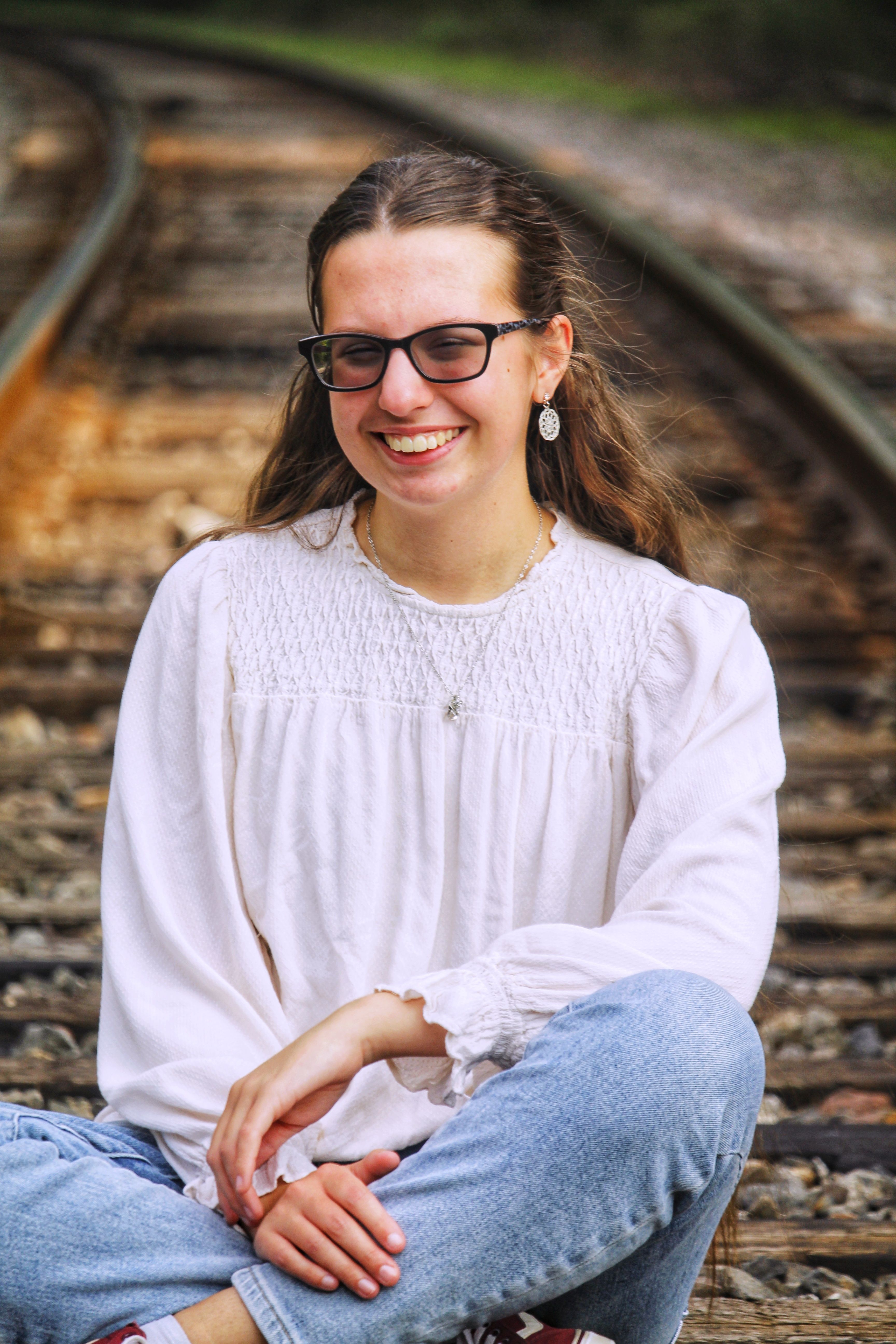 Smiling Woman in Casual Attire on Train Tracks · Free Stock Photo