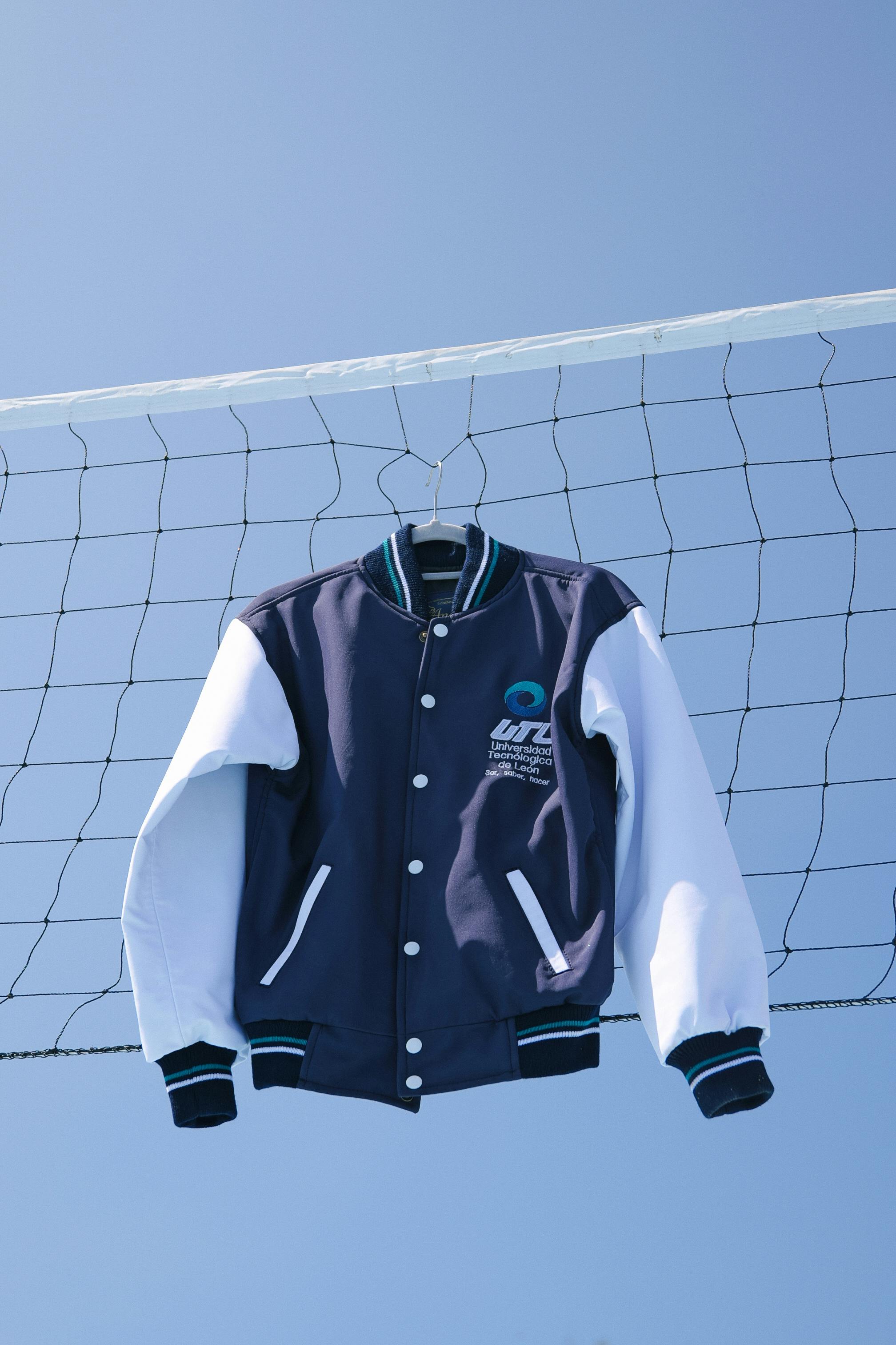 Varsity Jacket Hanging on Volleyball Net Outdoors · Free Stock Photo