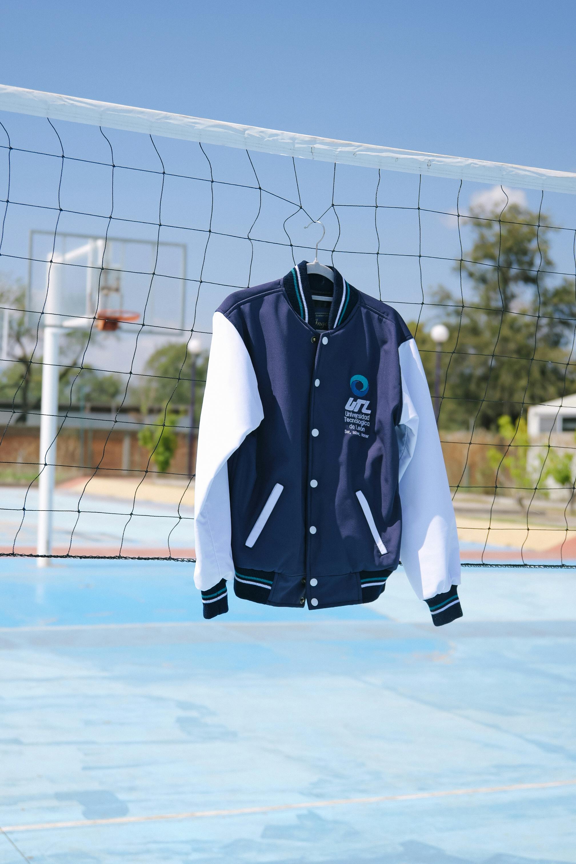 Casual Varsity Jacket Hanging on Net Outdoors · Free Stock Photo