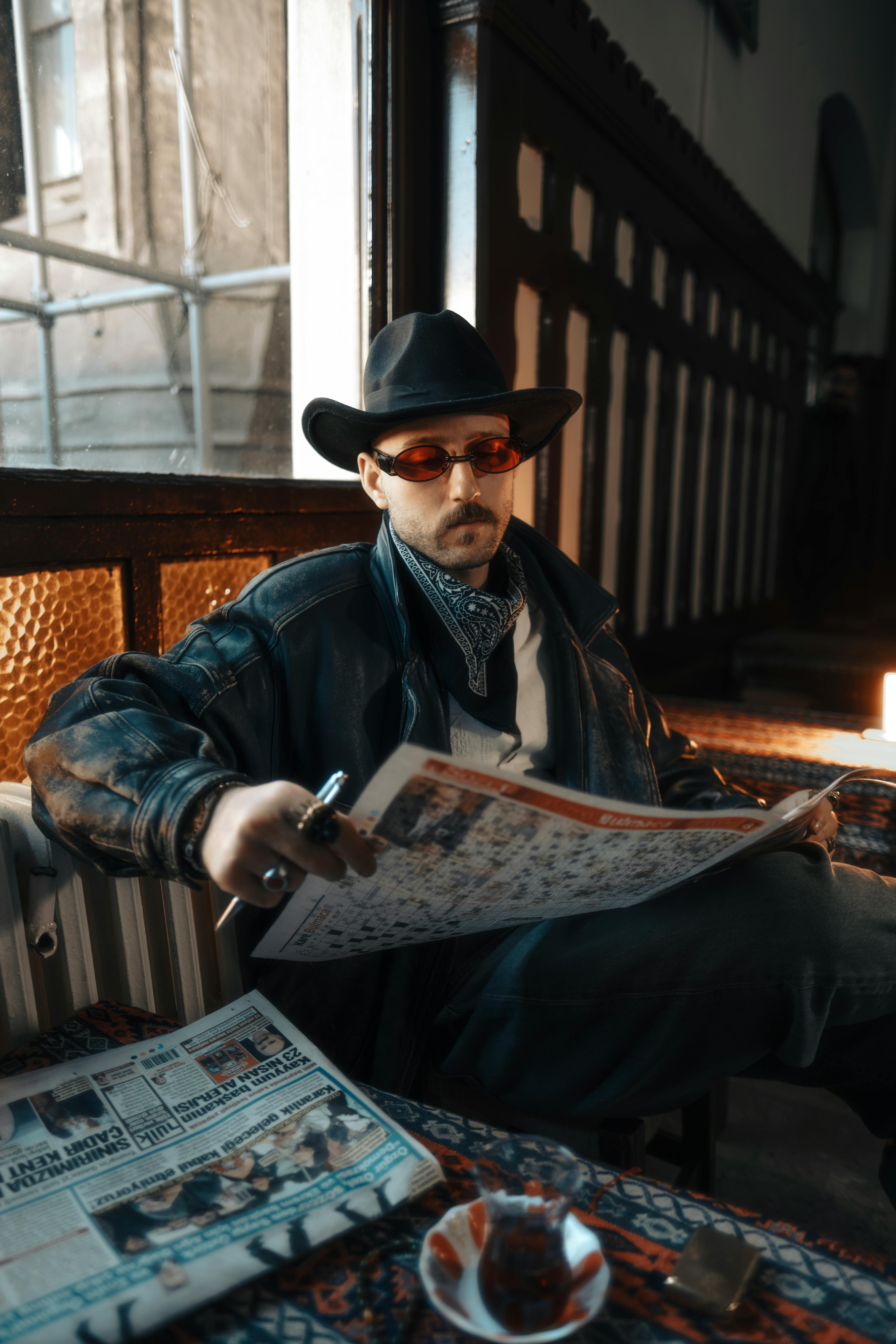 Stylish Cowboy Reading Newspaper Indoors · Free Stock Photo