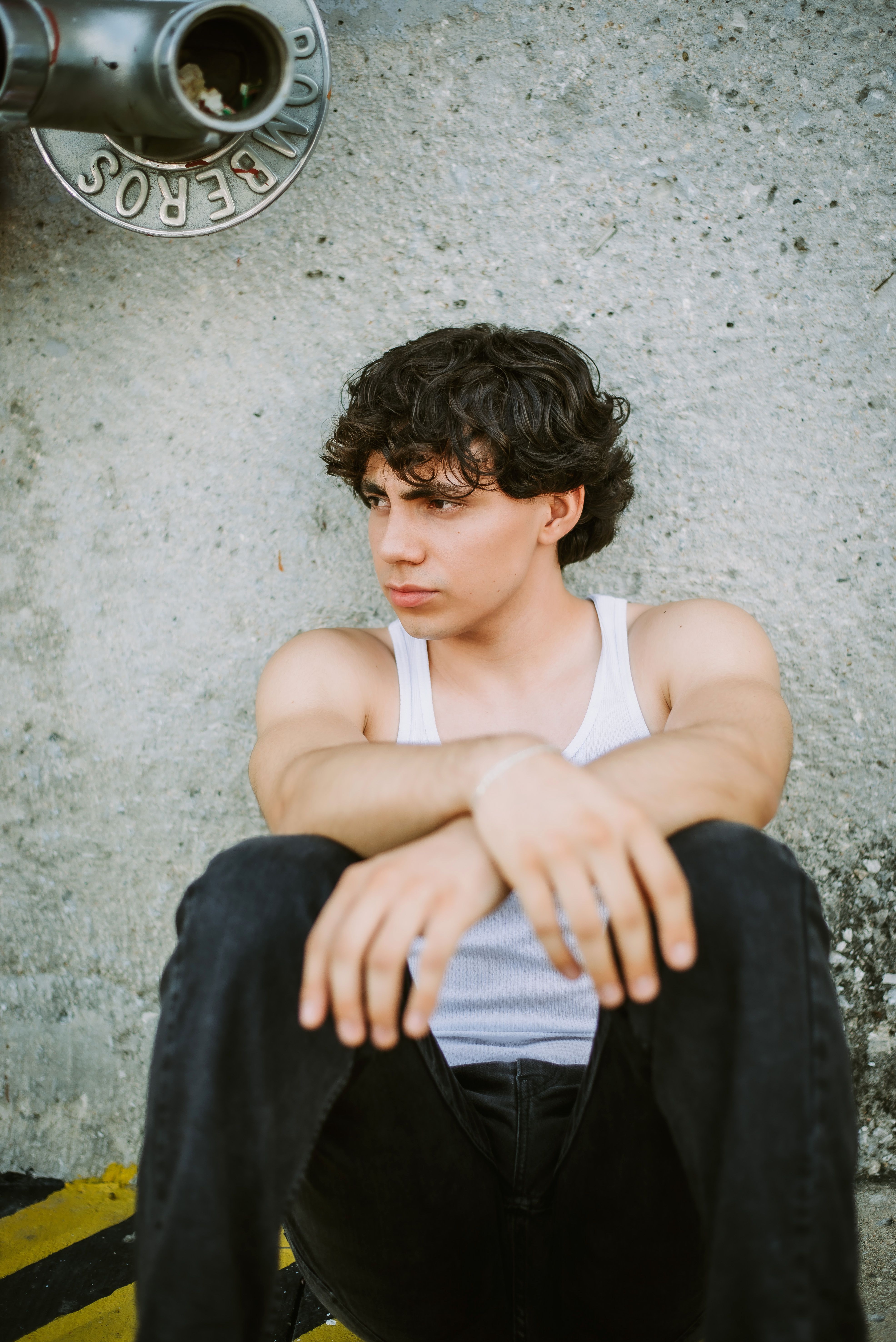 Young Man Sitting Against Urban Wall Outdoors · Free Stock Photo