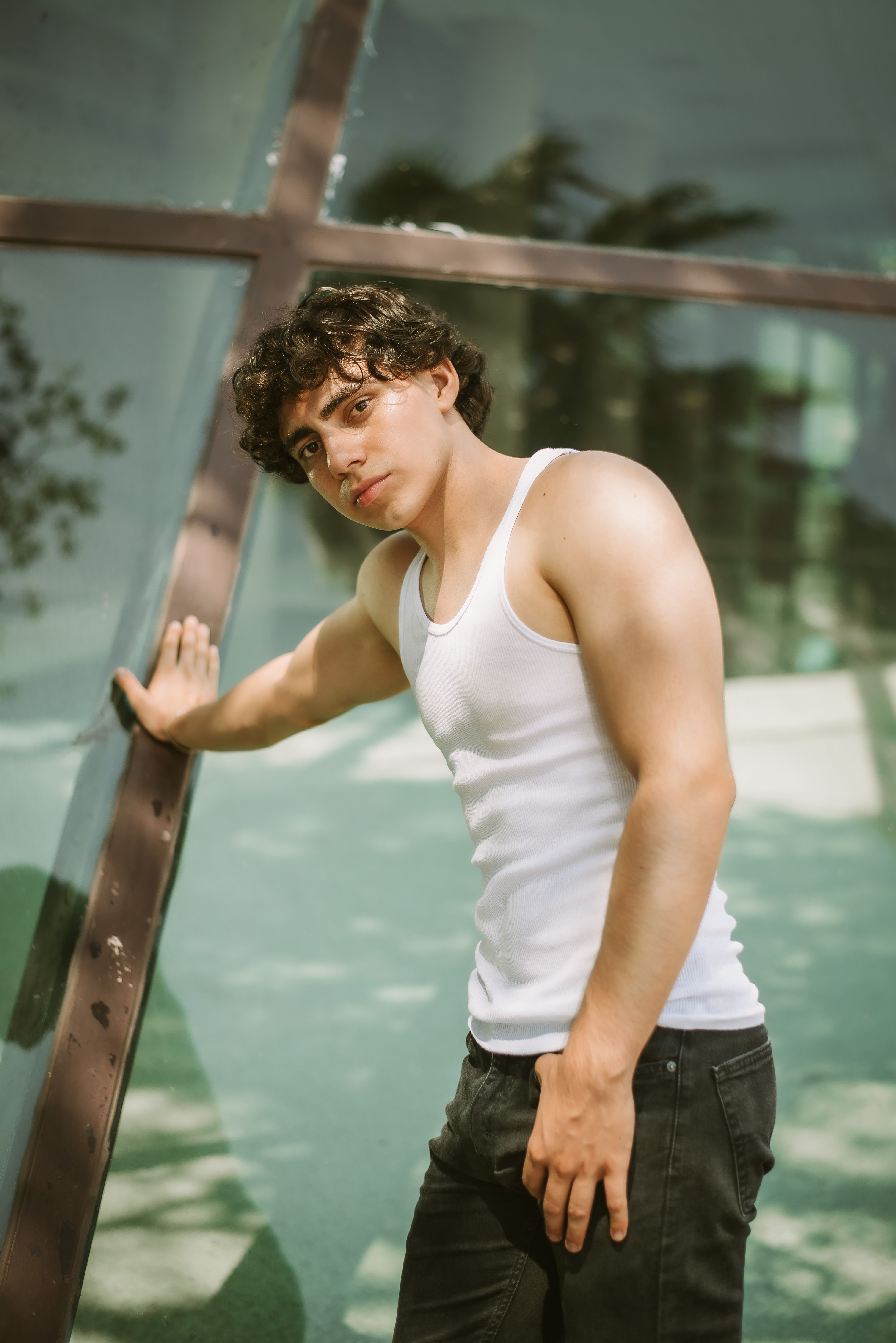 Young Man Leaning Against Glass Outdoors · Free Stock Photo