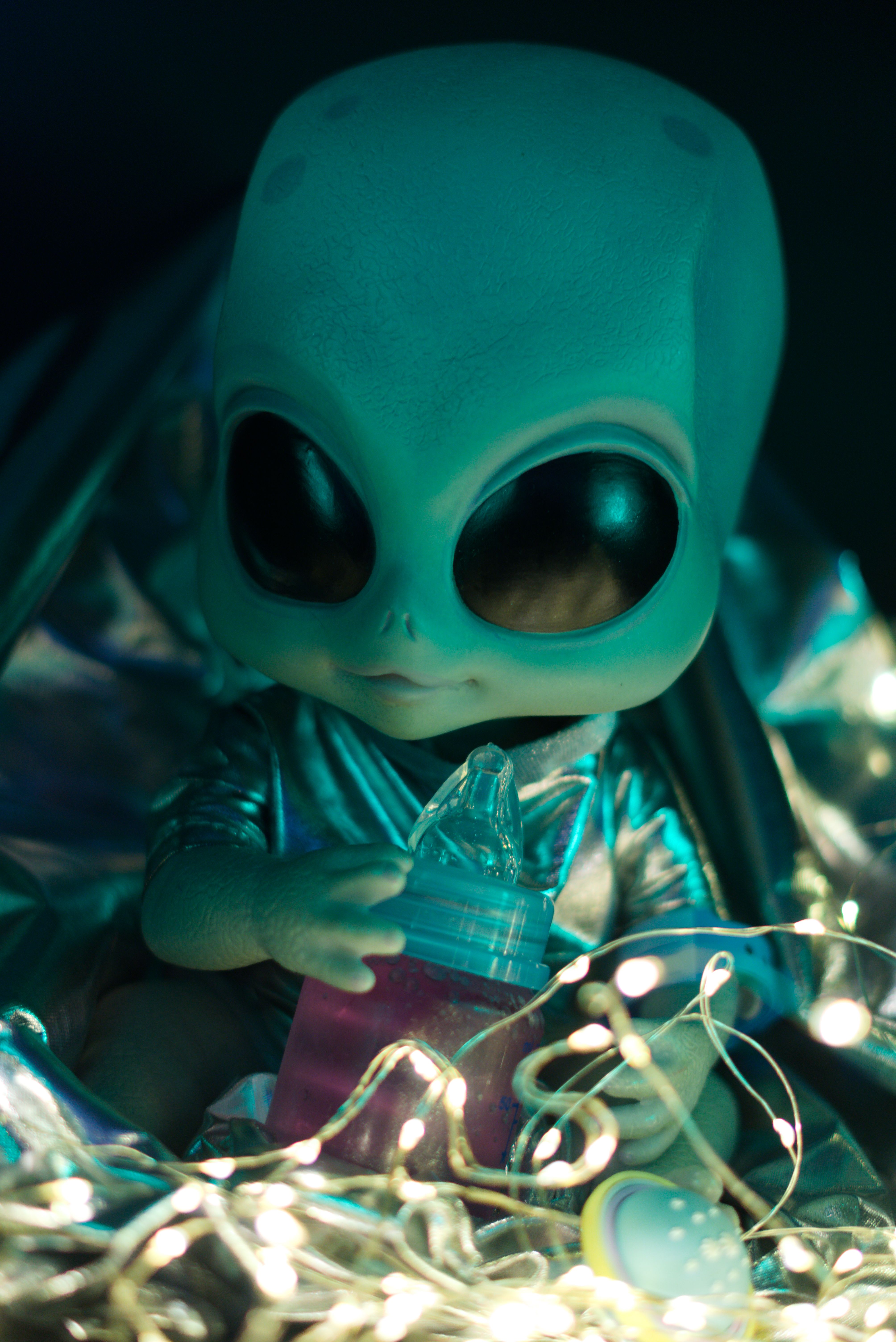 Alien Baby Holding Bottle in Starry Setting · Free Stock Photo