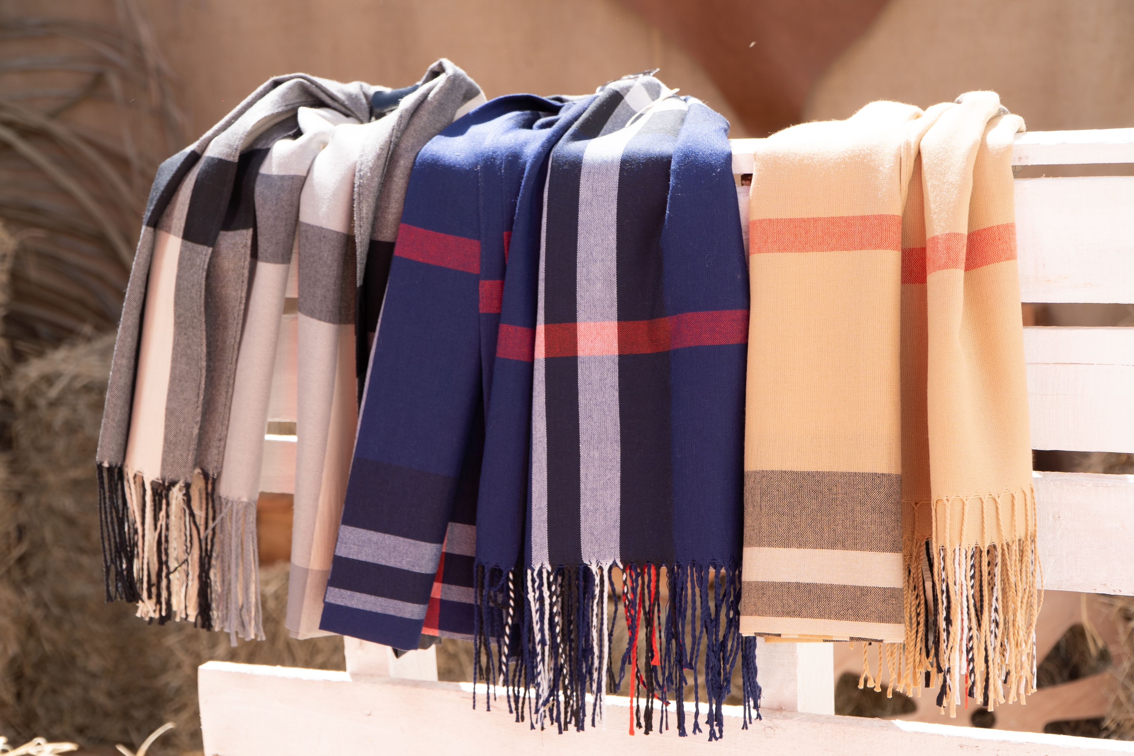 Colorful Wool Scarves Hanging on Wooden Rack Outdoors · Free Stock Photo