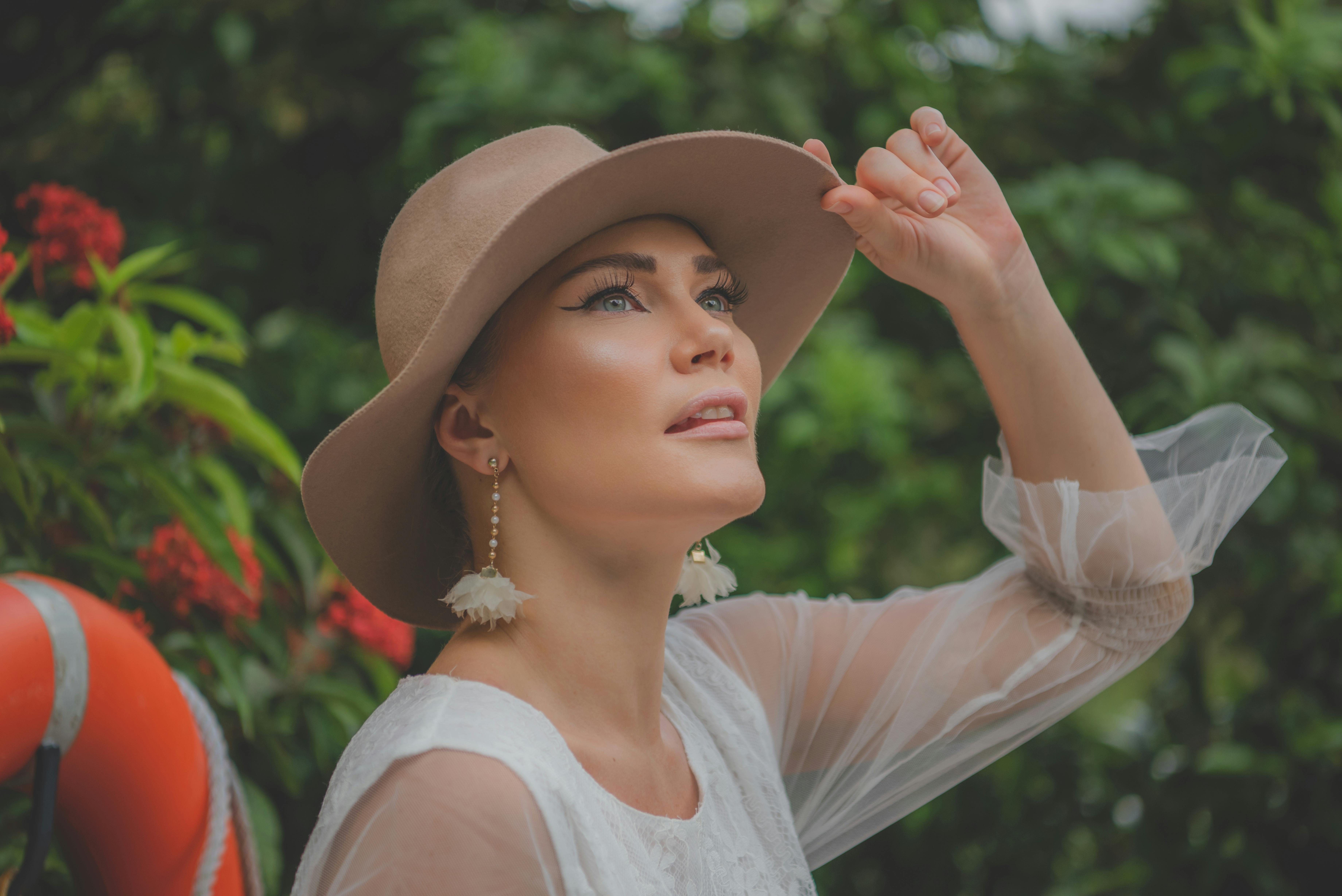 Elegant Woman in Hat Outdoors with Greenery · Free Stock Photo