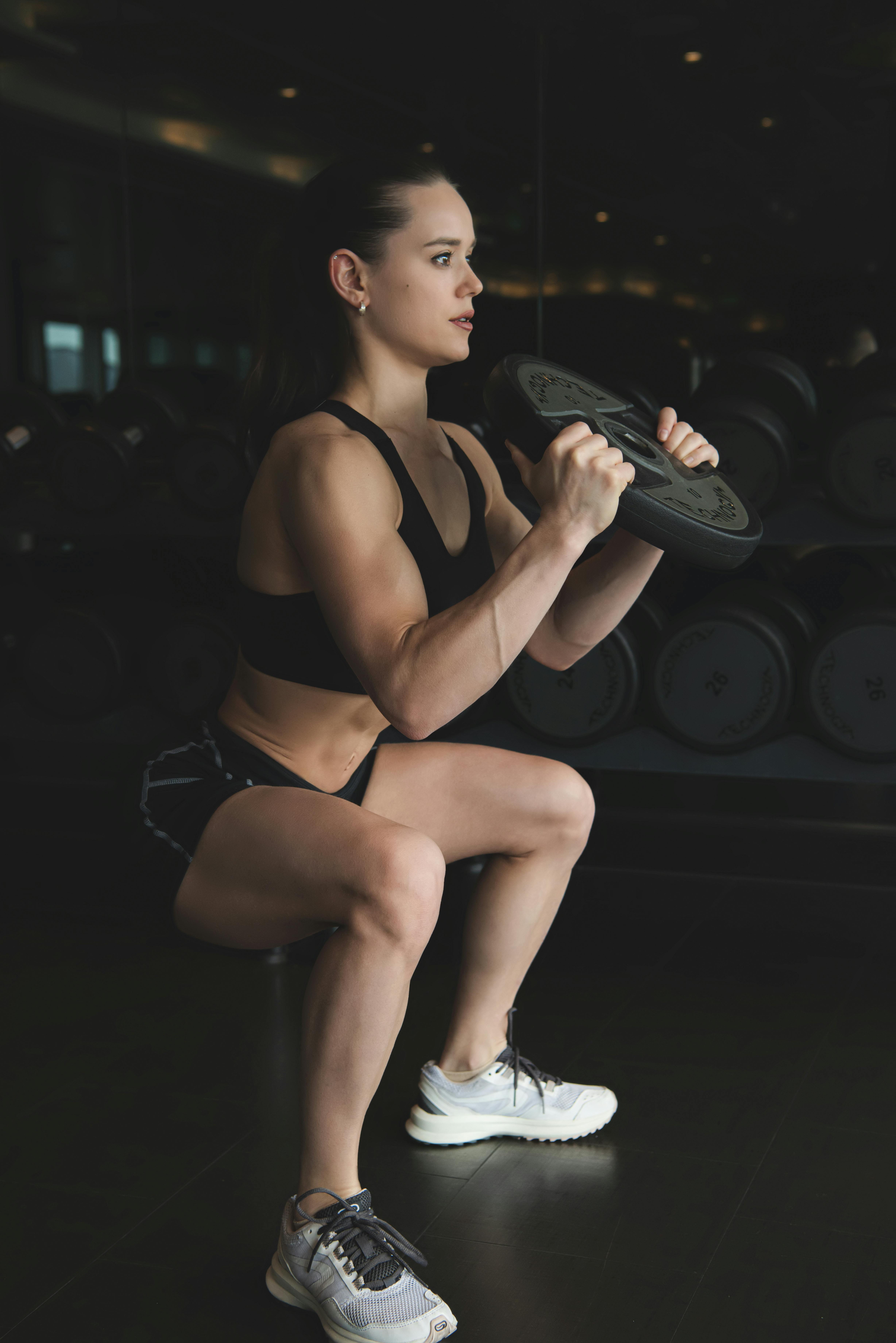 Woman Performing Weighted Squat in Gym · Free Stock Photo