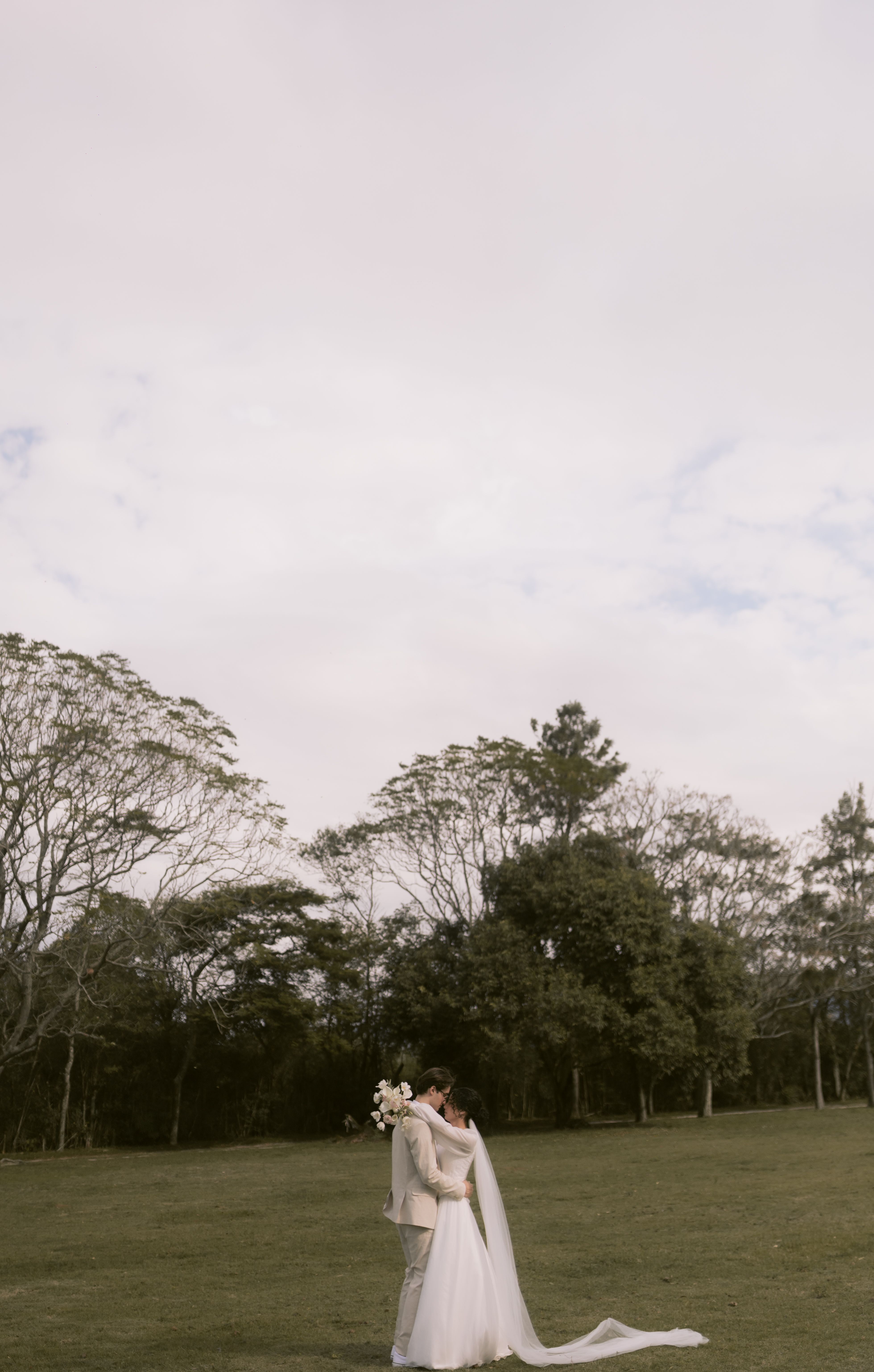 Romantic Outdoor Wedding Embrace Under Cloudy Sky · Free Stock Photo