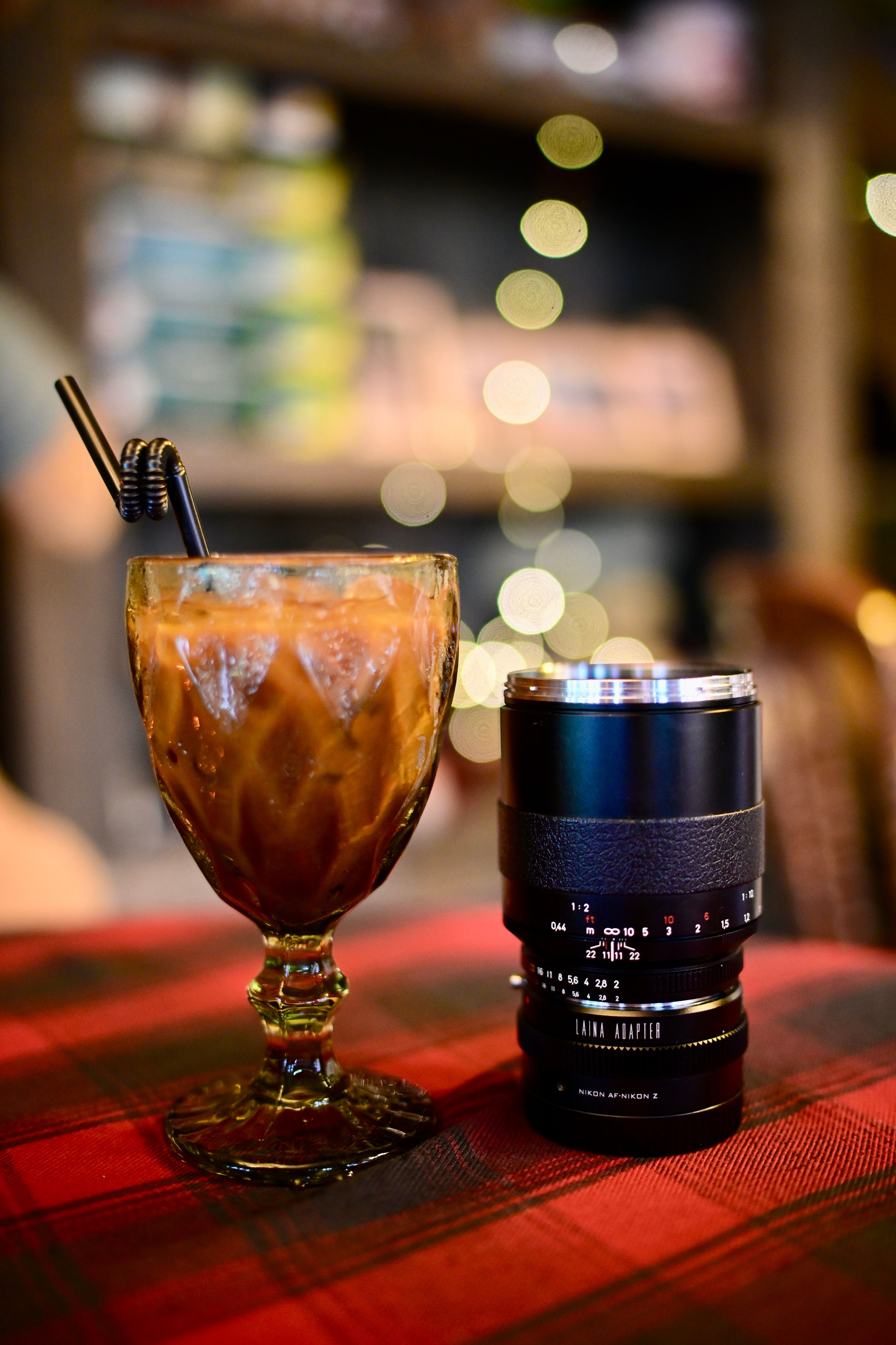 Iced Coffee and Camera Lens on Plaid Table · Free Stock Photo