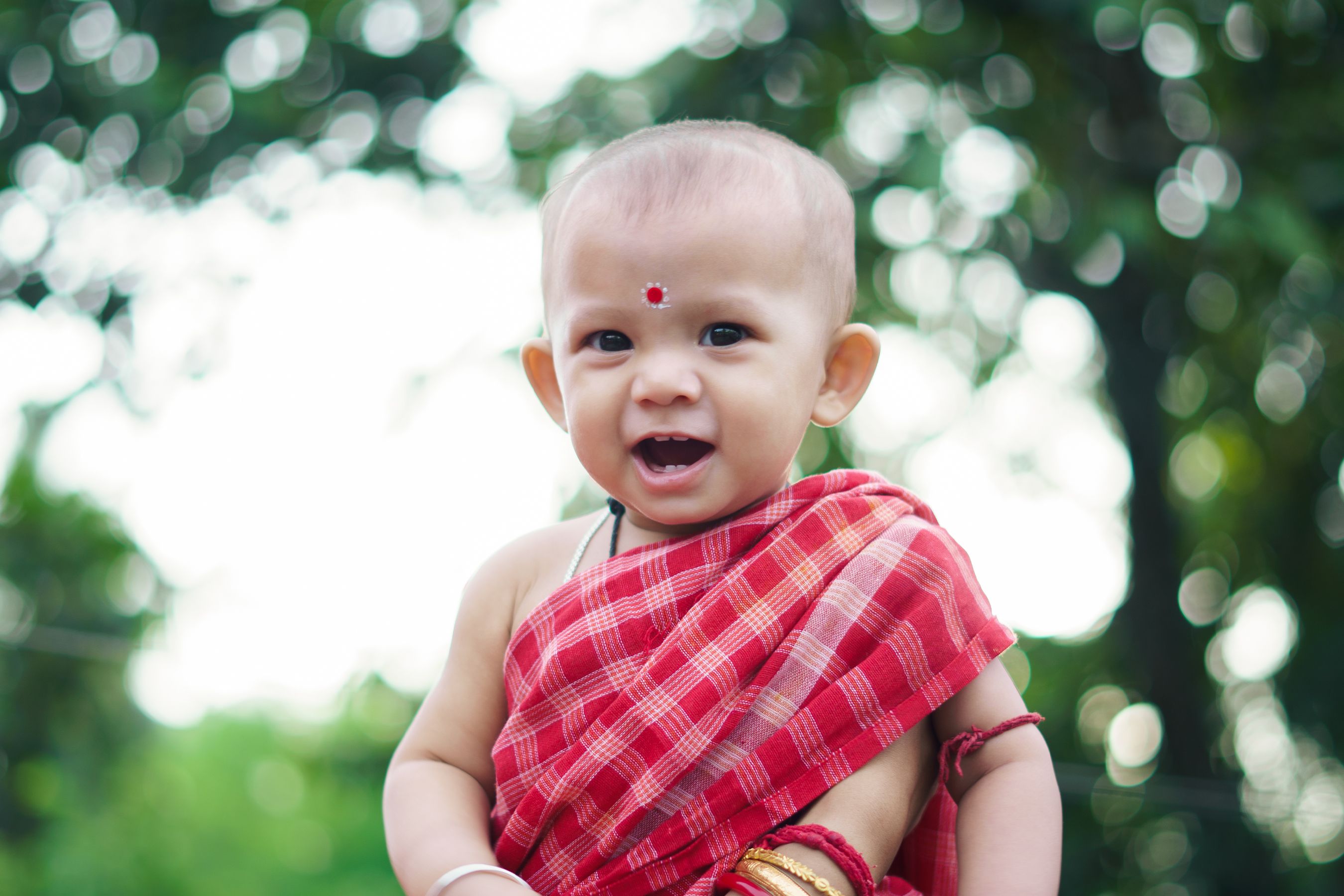 Adorable Baby Smiling in Traditional Attire Outdoors · Free Stock Photo