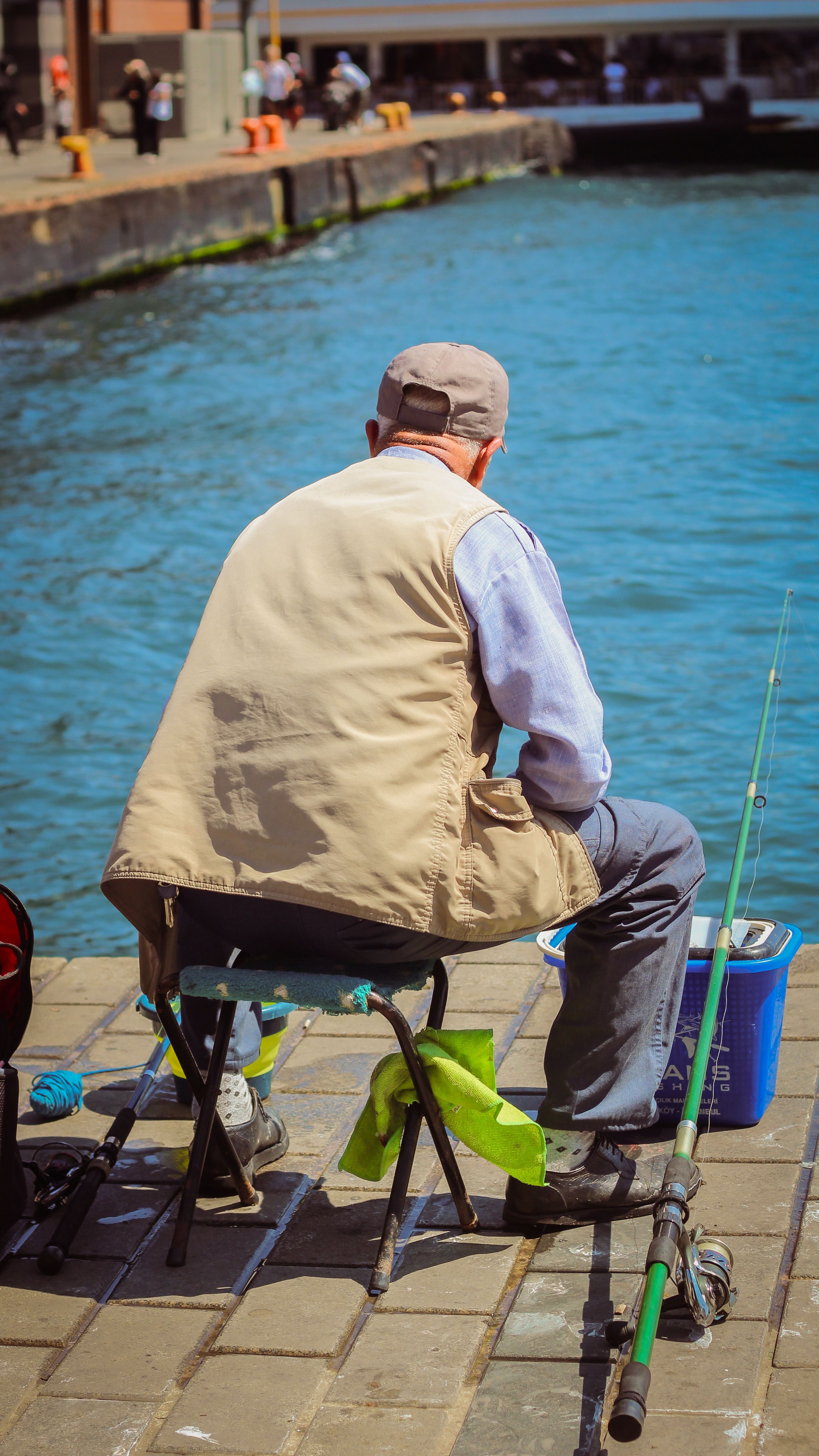 Elderly Man Fishing on Urban Dockside · Free Stock Photo