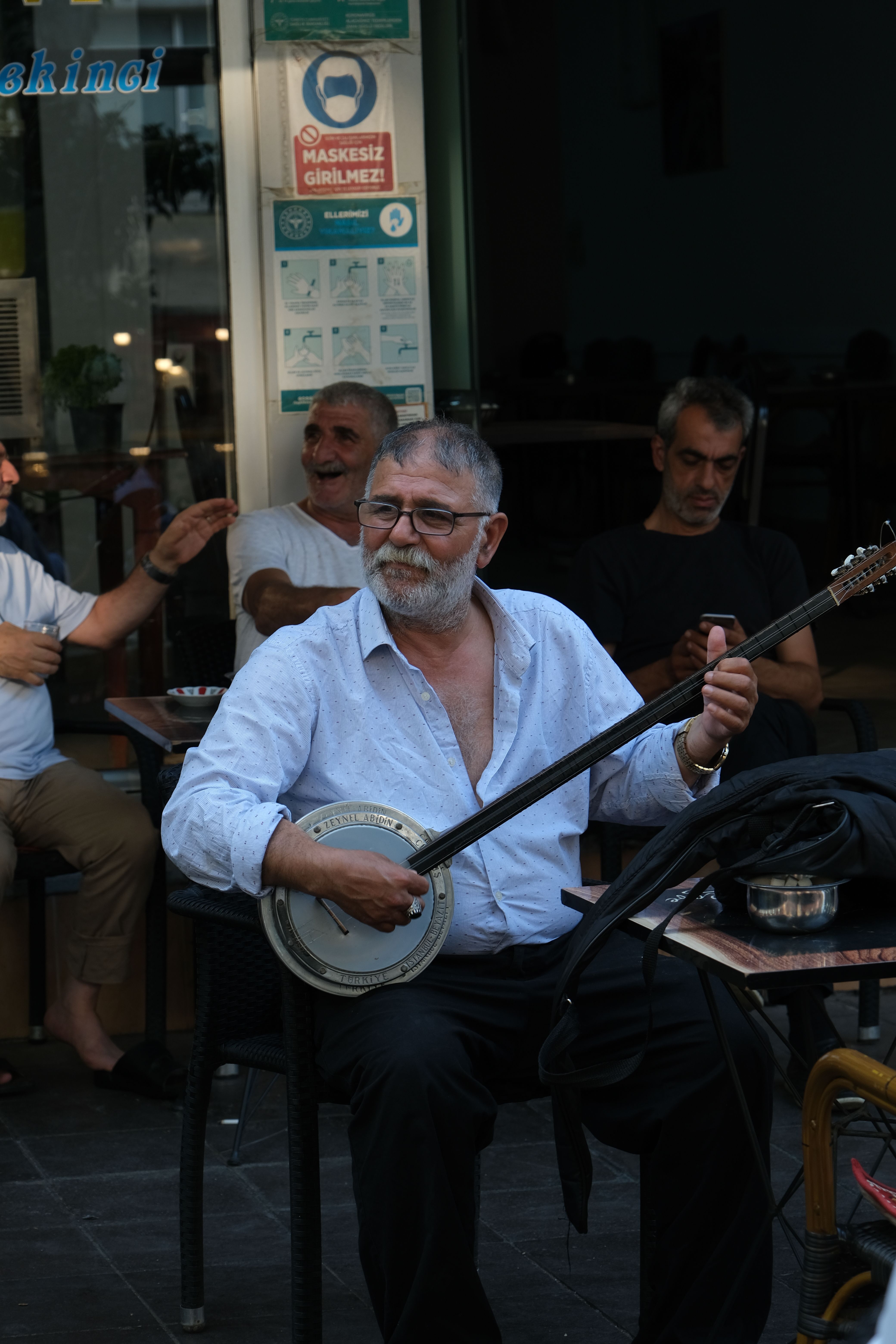 Musician Playing Banjo at Outdoor Café · Free Stock Photo