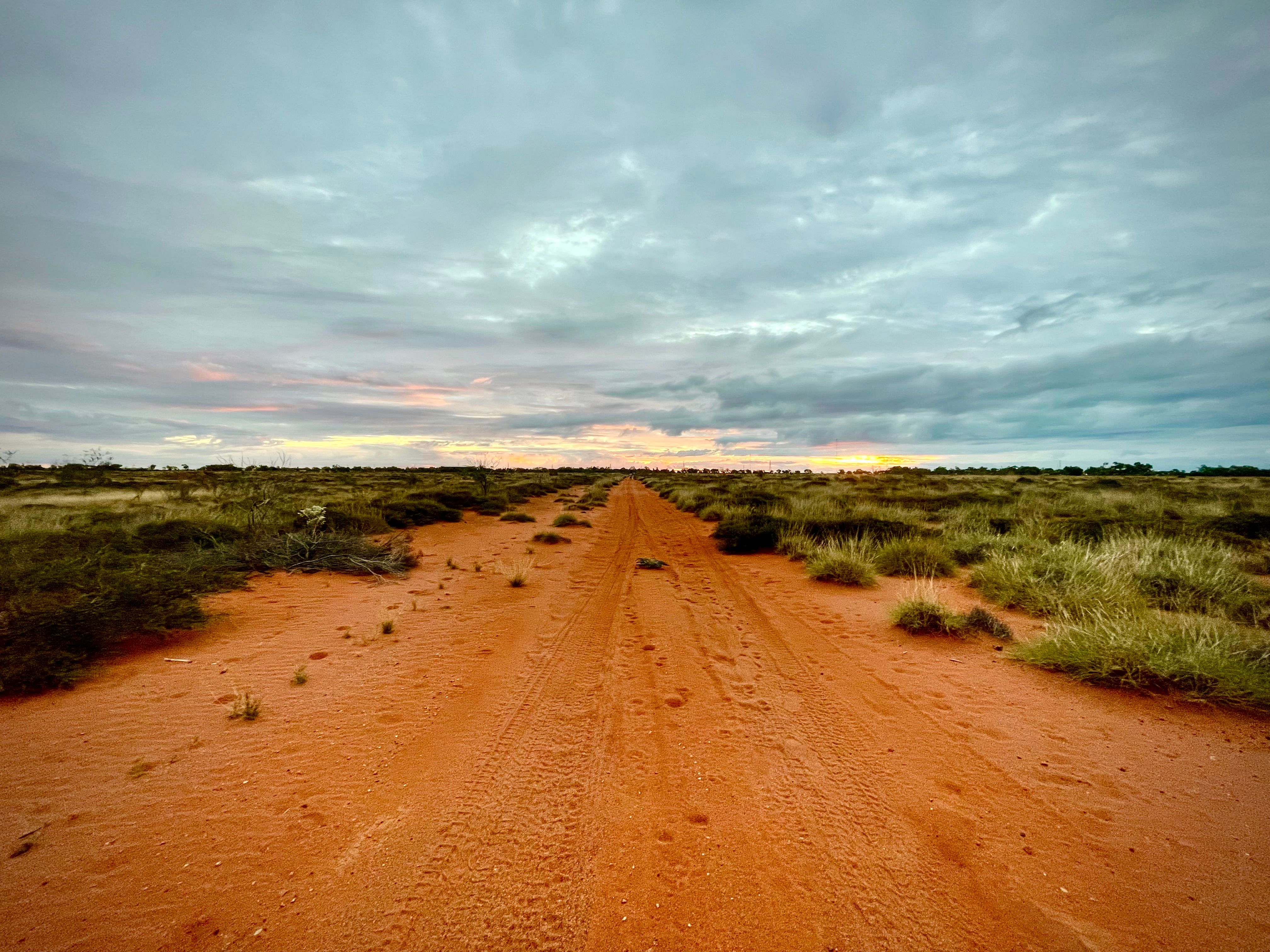 Vibrant Red Dirt Road in Arid Landscape at Sunset · Free Stock Photo