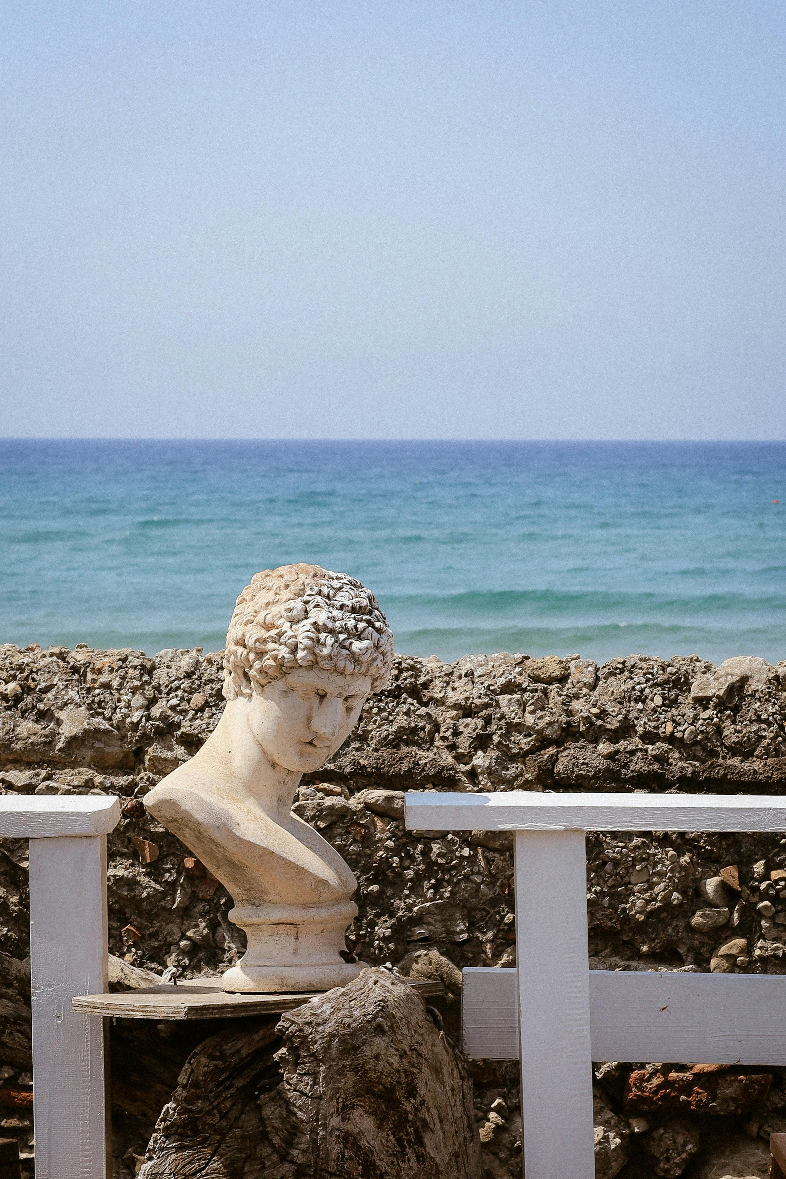 Classical Bust Overlooking Ocean with Rustic Wall · Free Stock Photo