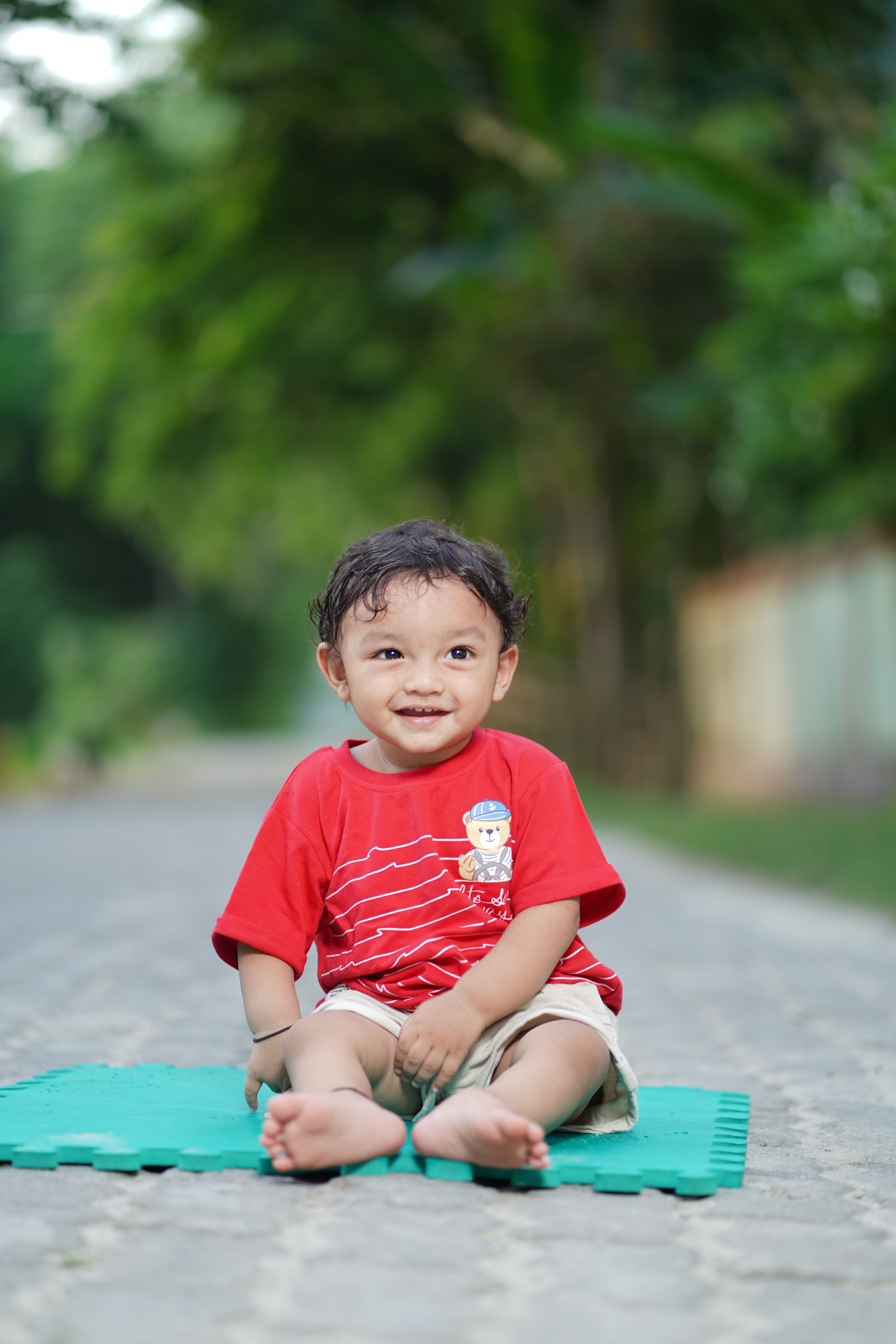 Smiling Toddler Sitting Outdoors on Play Mat · Free Stock Photo