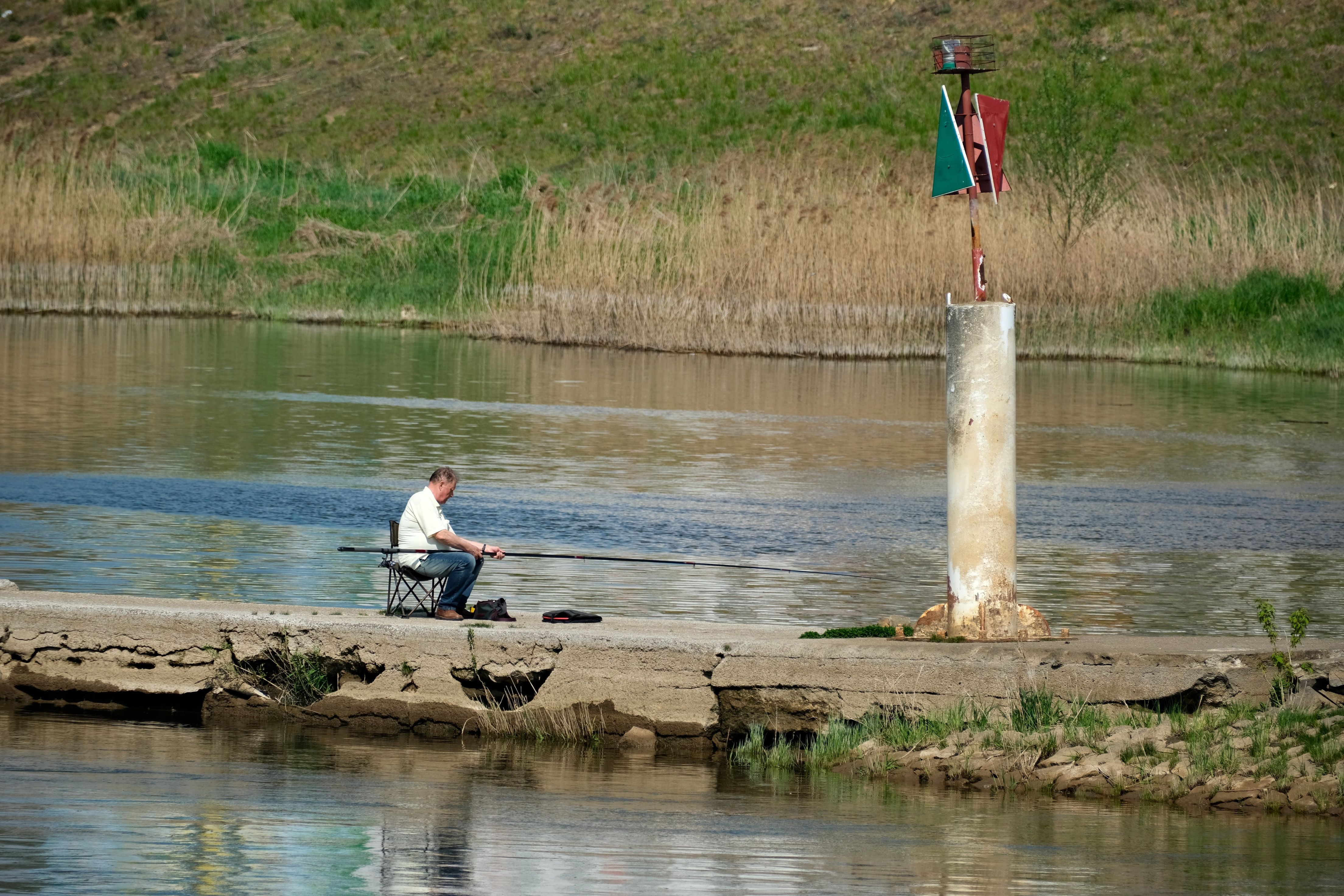 Man Fishing by Riverside on a Peaceful Spring Day · Free Stock Photo