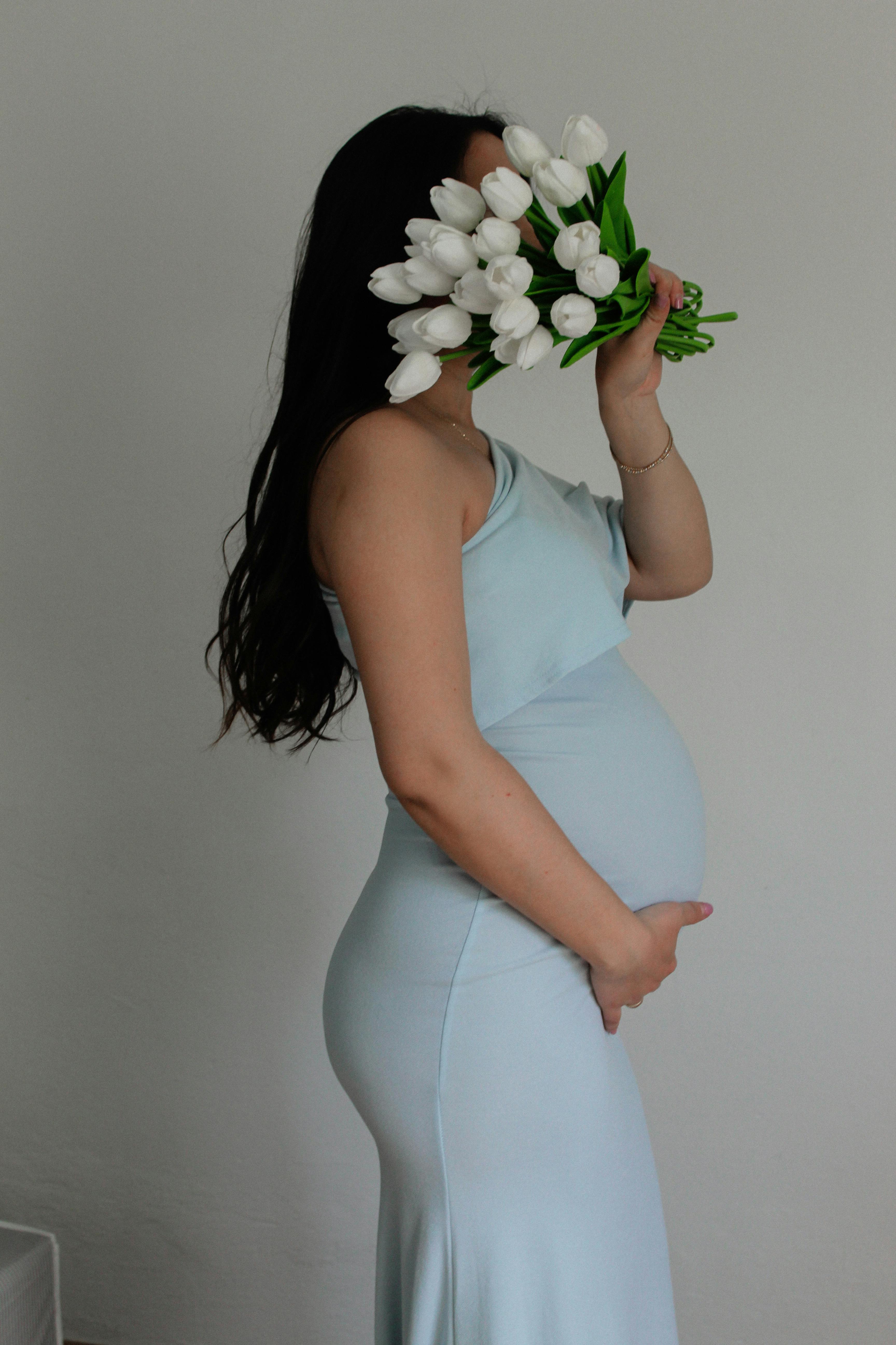 Pregnant Woman Holding White Tulips Elegantly · Free Stock Photo