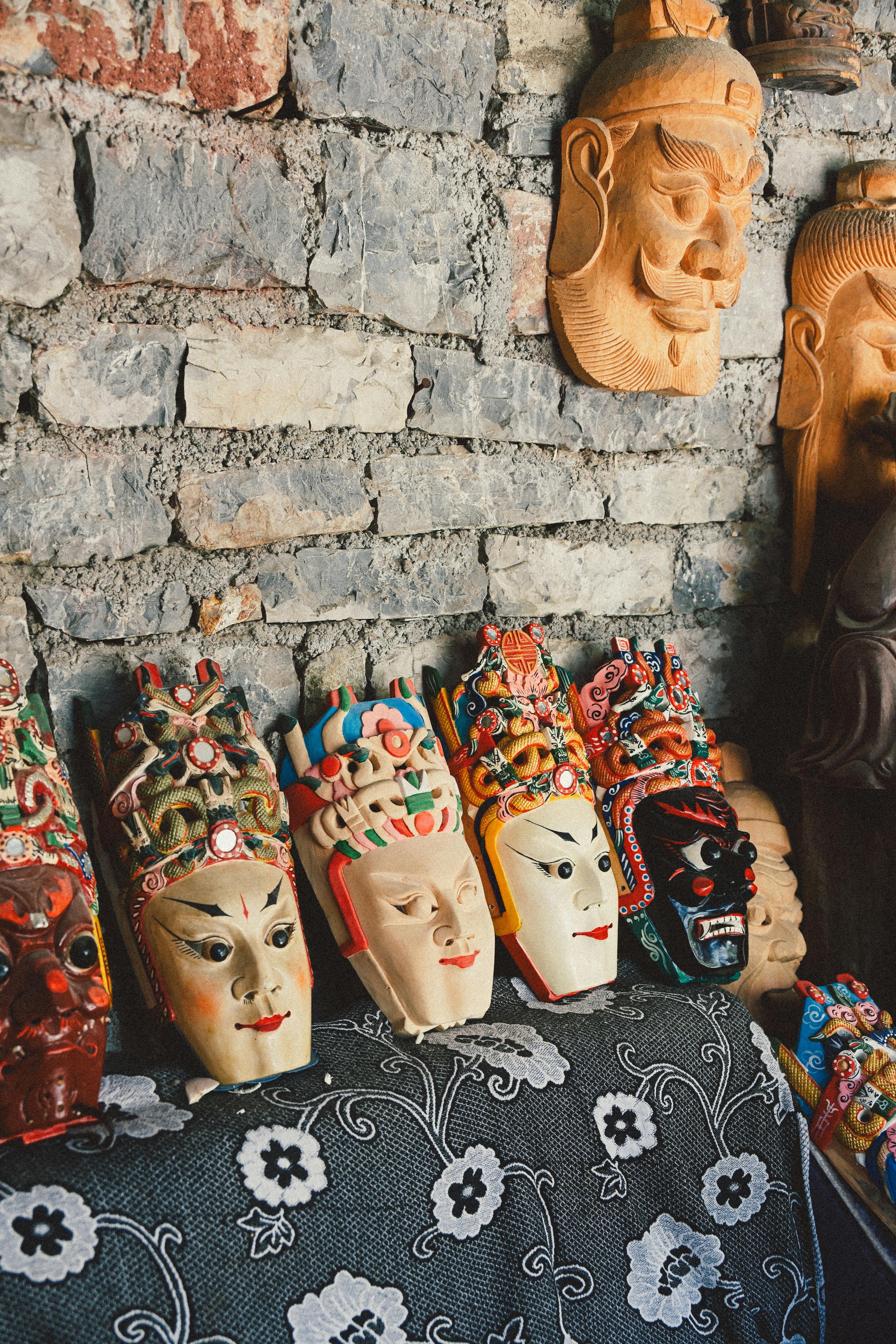 Colorful Traditional Masks Display on Rustic Wall · Free Stock Photo