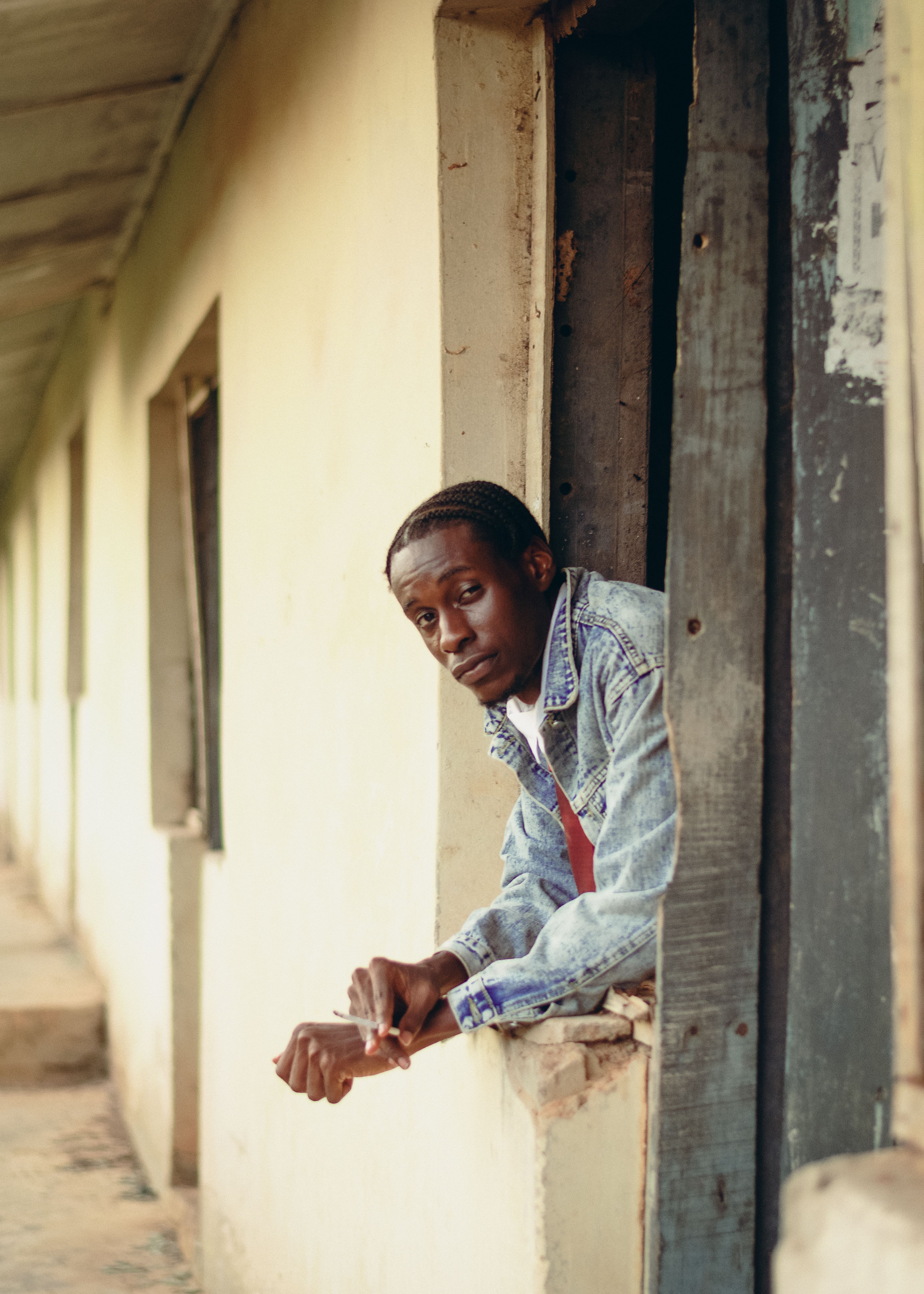 Man Leaning Out of Window in Casual Denim Jacket · Free Stock Photo