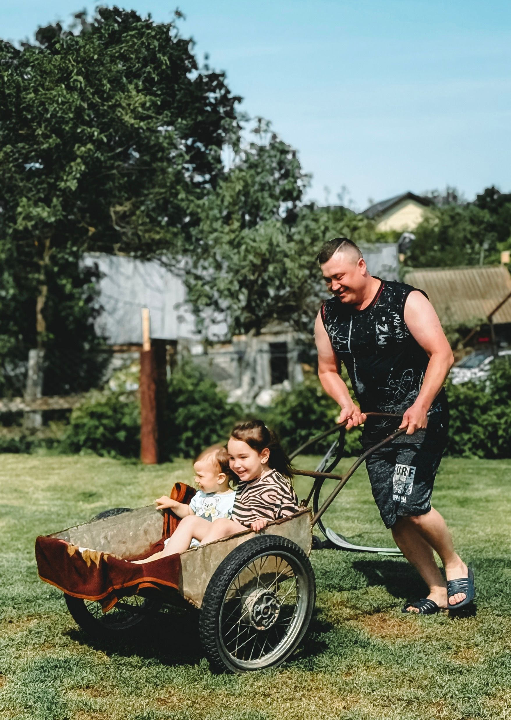 Father Enjoying Playful Cart Ride with Kids Outdoors · Free Stock Photo