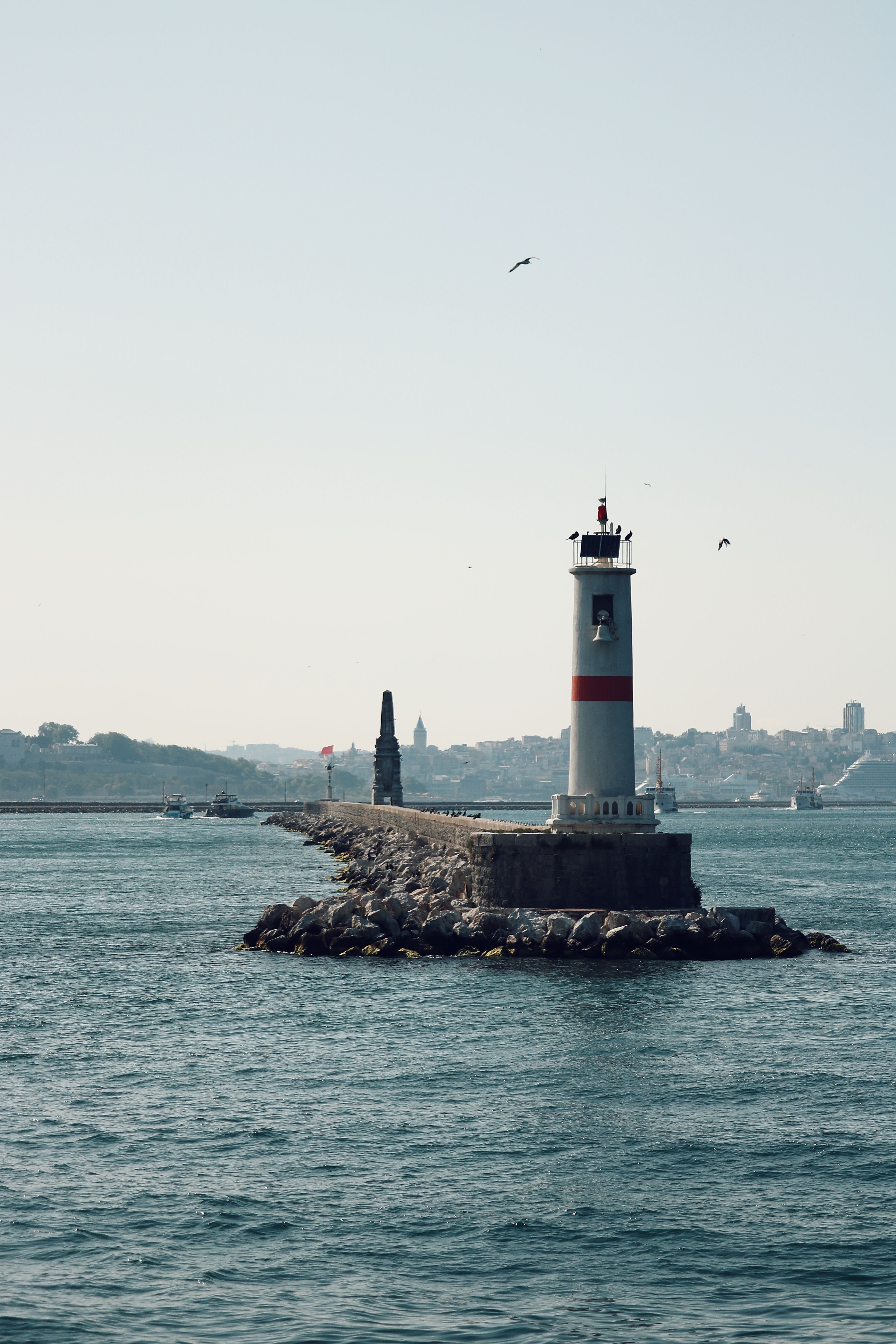 Guiding Lighthouse with City Skyline Backdrop · Free Stock Photo