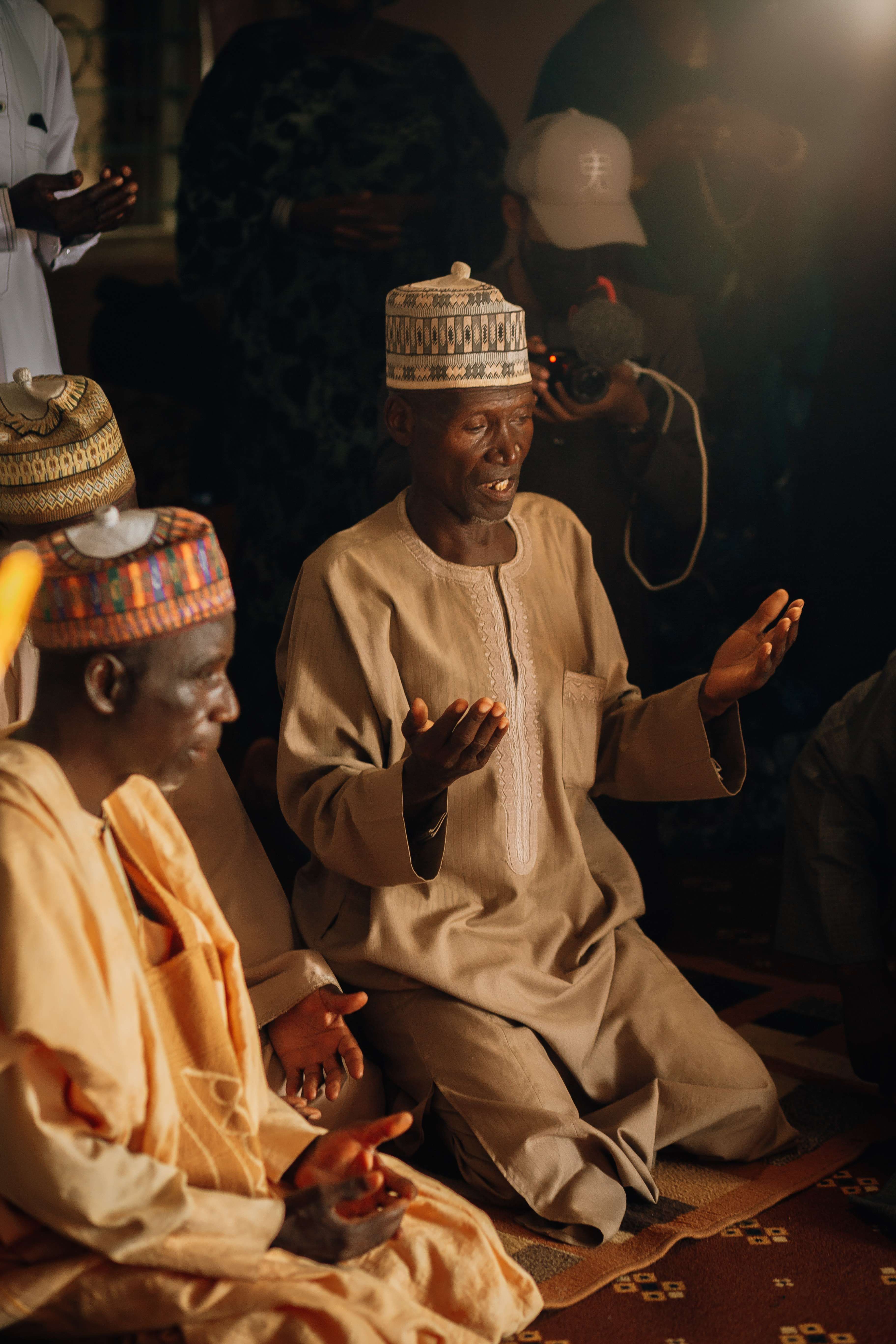 Group of Men Praying Outdoors in Colorful Attire · Free Stock Photo