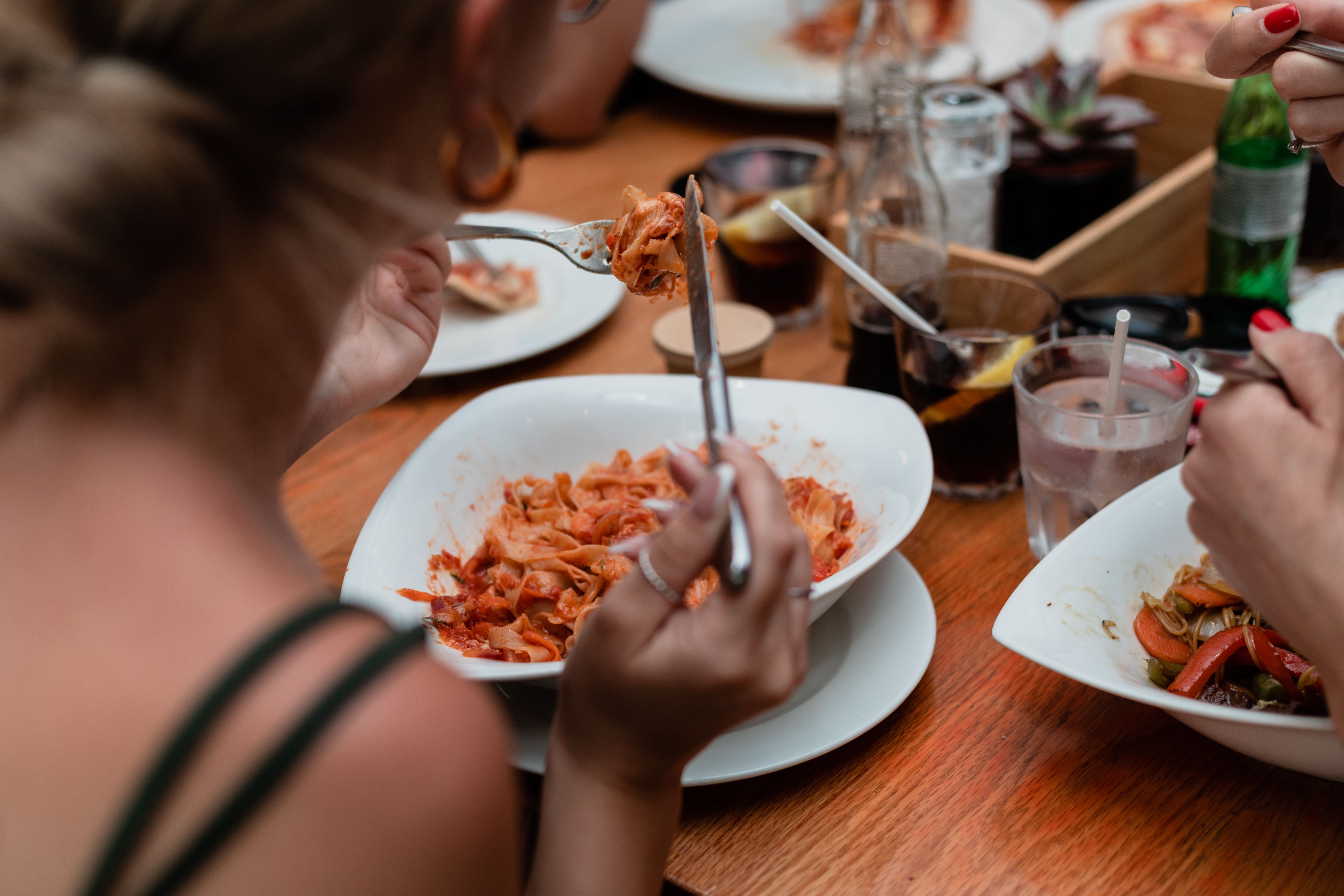 Close-up of friends dining on pasta at restaurant · Free Stock Photo