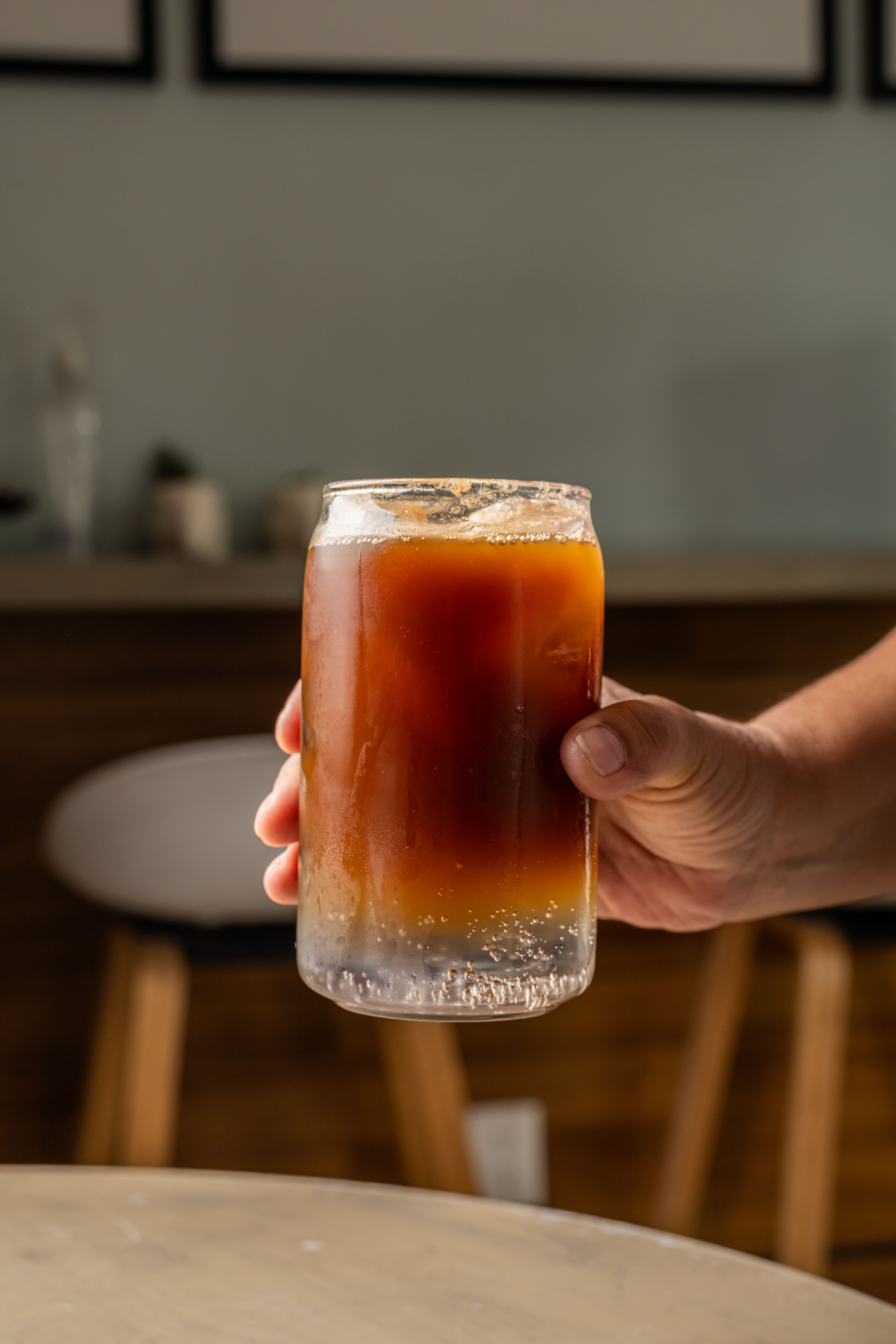 Hand Holding a Cold Brew Coffee in Cafe Setting · Free Stock Photo