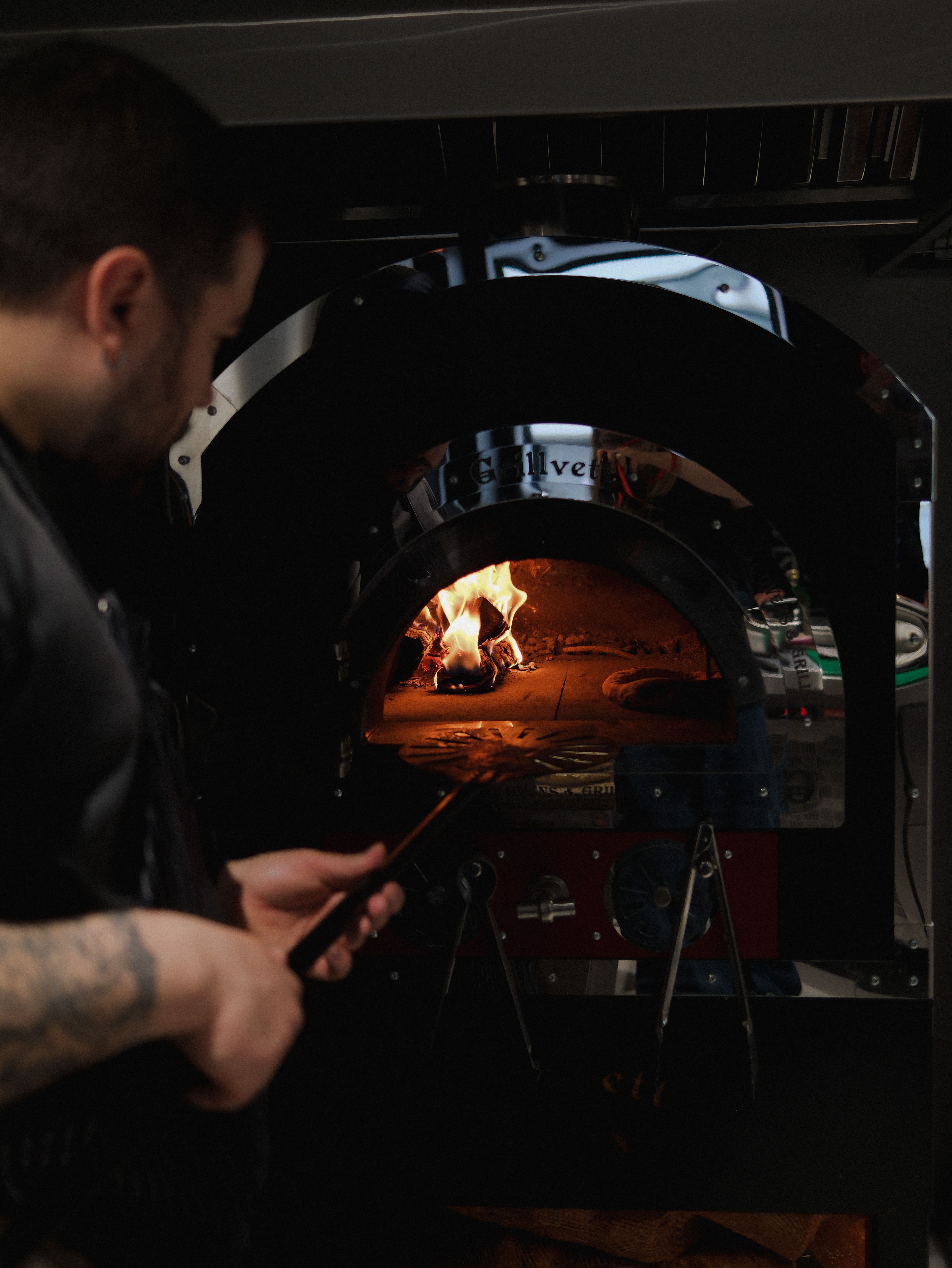 Baker using wood-fired oven in modern kitchen · Free Stock Photo