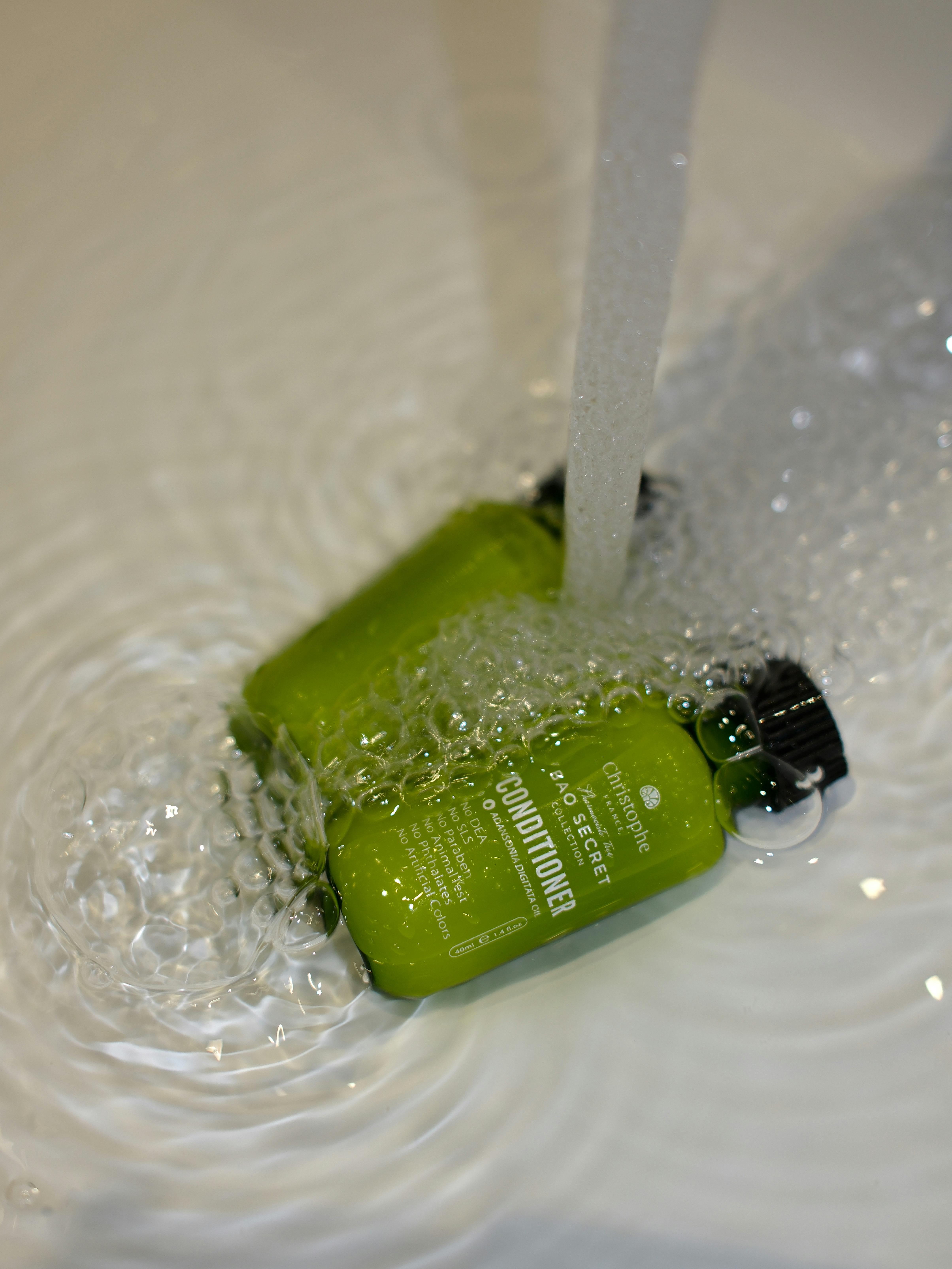 Green Shampoo Bottles in Running Water · Free Stock Photo