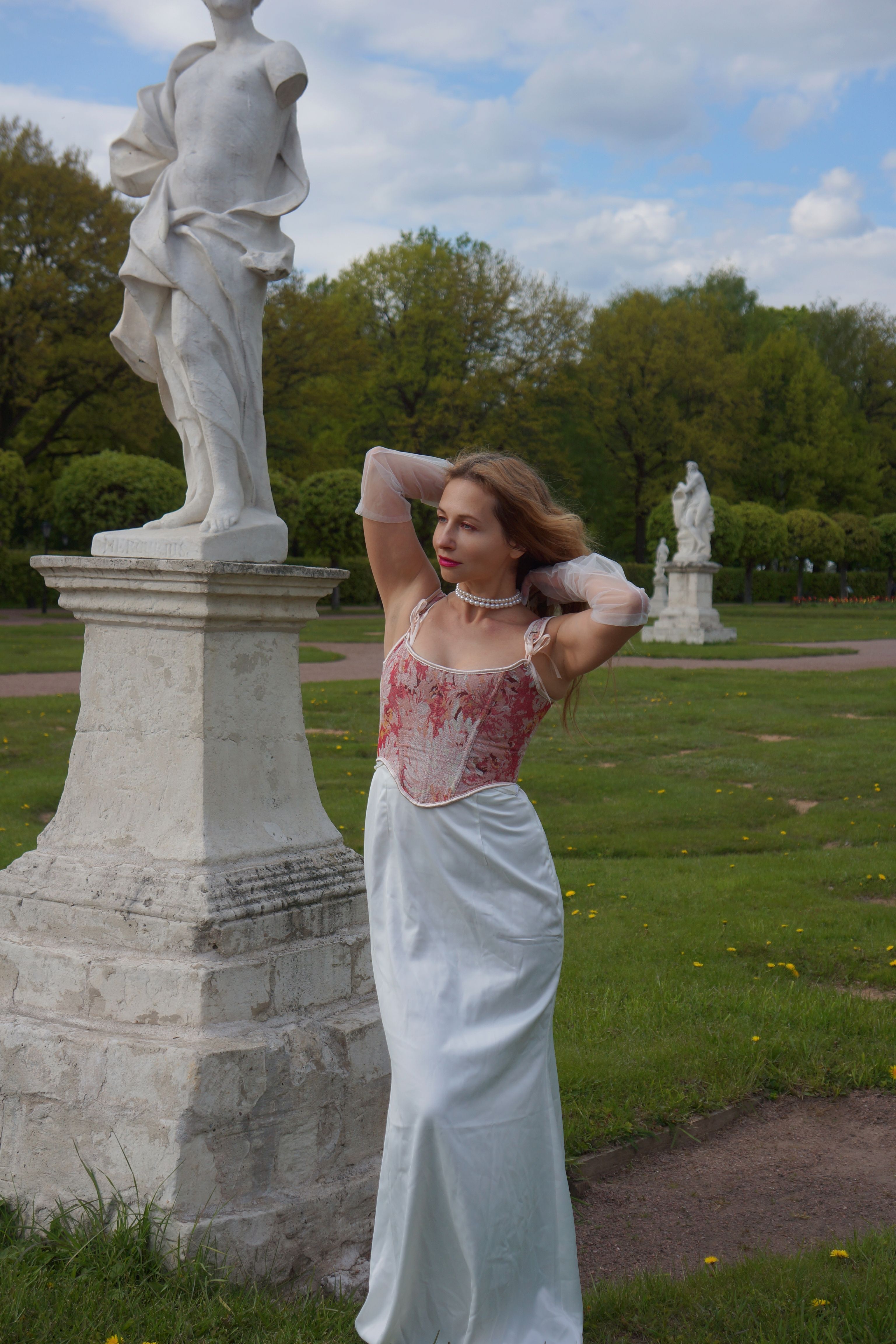 Elegantly Dressed Woman Posing by Classical Statues · Free Stock Photo