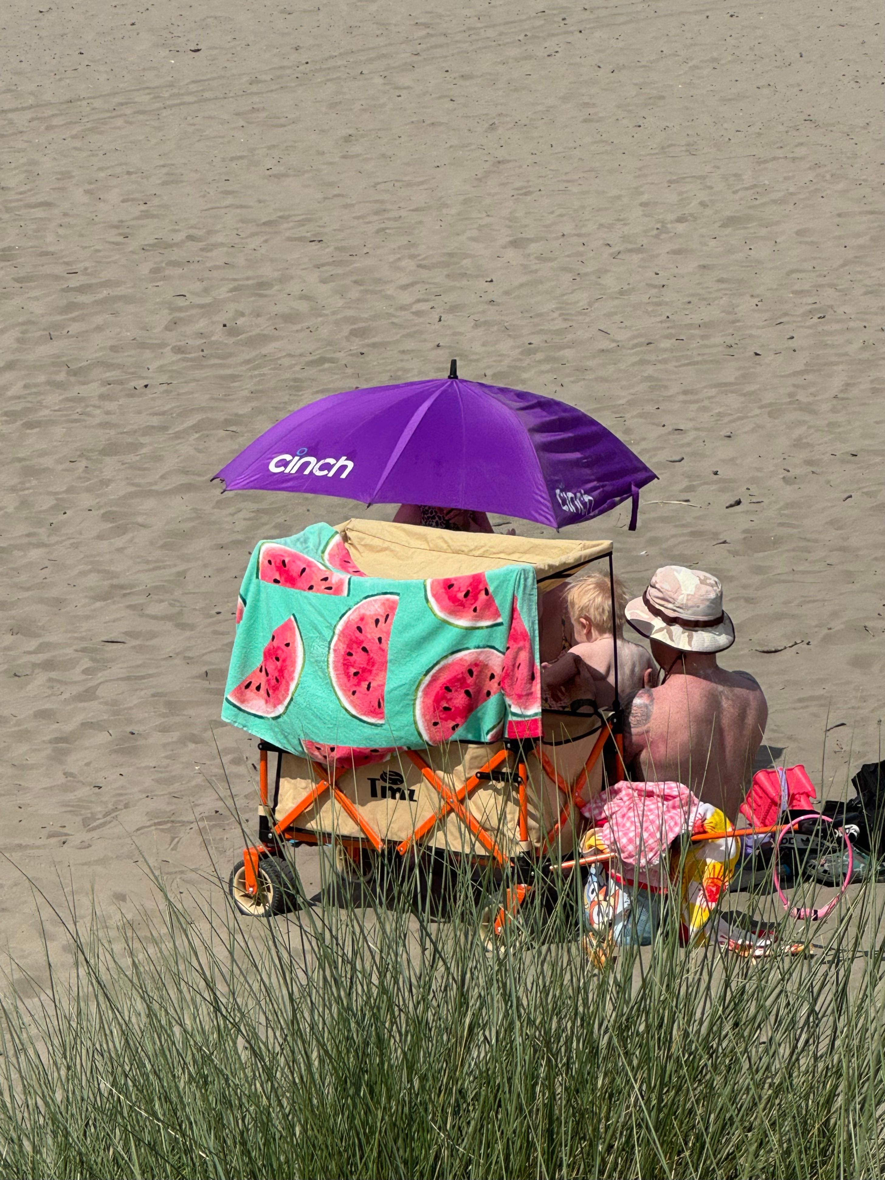 Family Beach Outing Under Vibrant Umbrella · Free Stock Photo