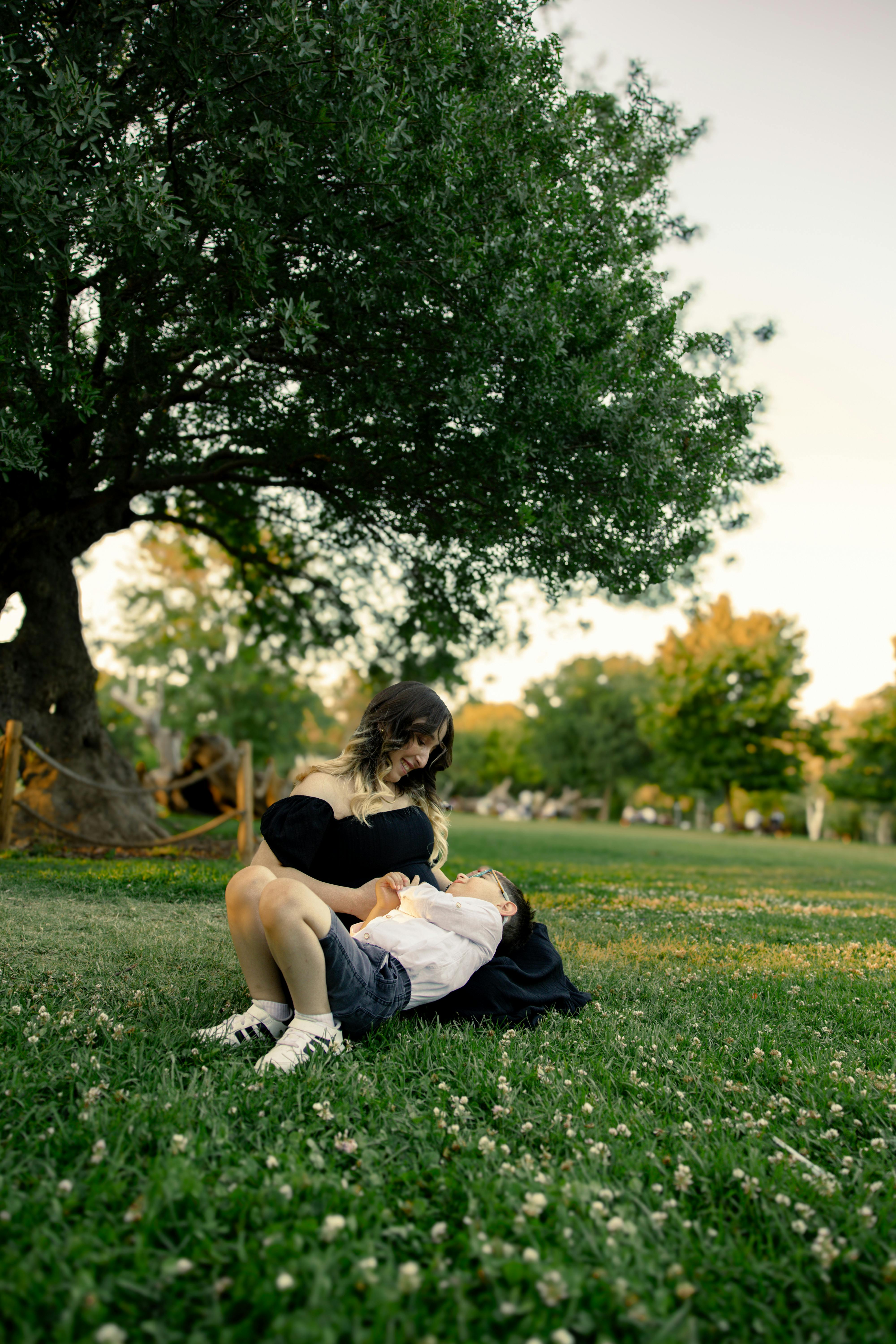 Mother and Child Relaxing Under Tree in Park · Free Stock Photo