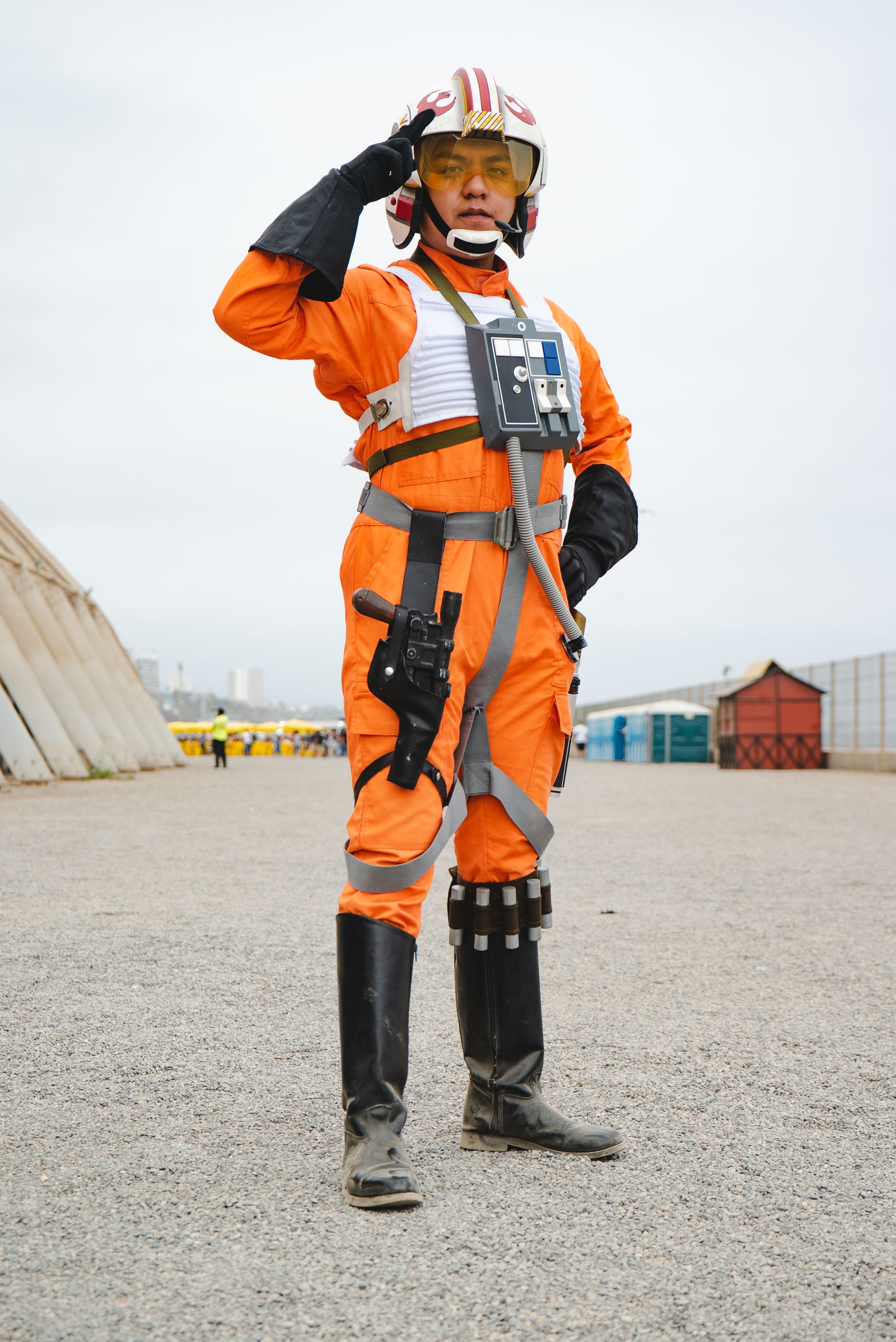 Person in orange pilot costume saluting outdoors · Free Stock Photo