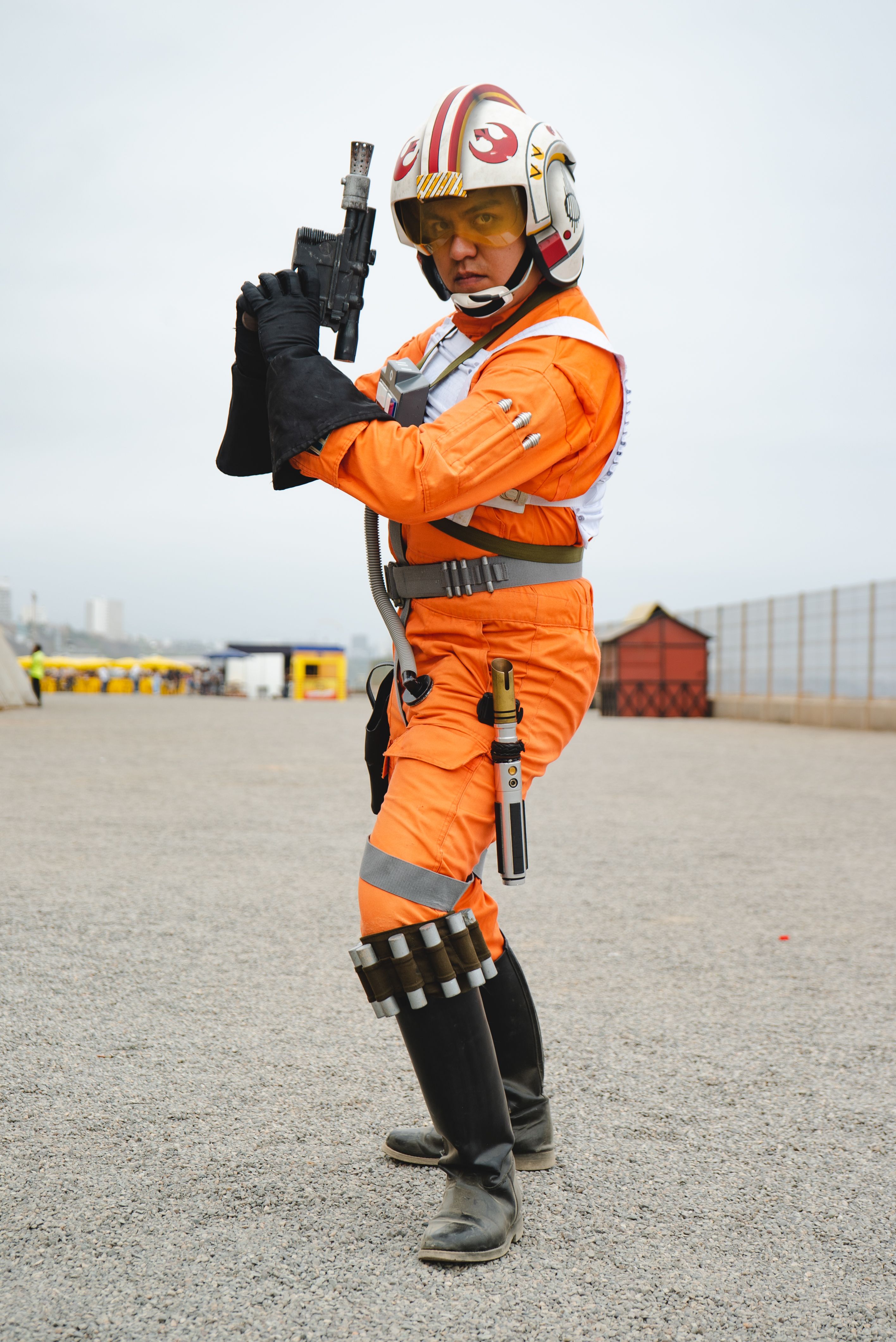 Cosplayer in Orange Pilot Costume with Blaster · Free Stock Photo