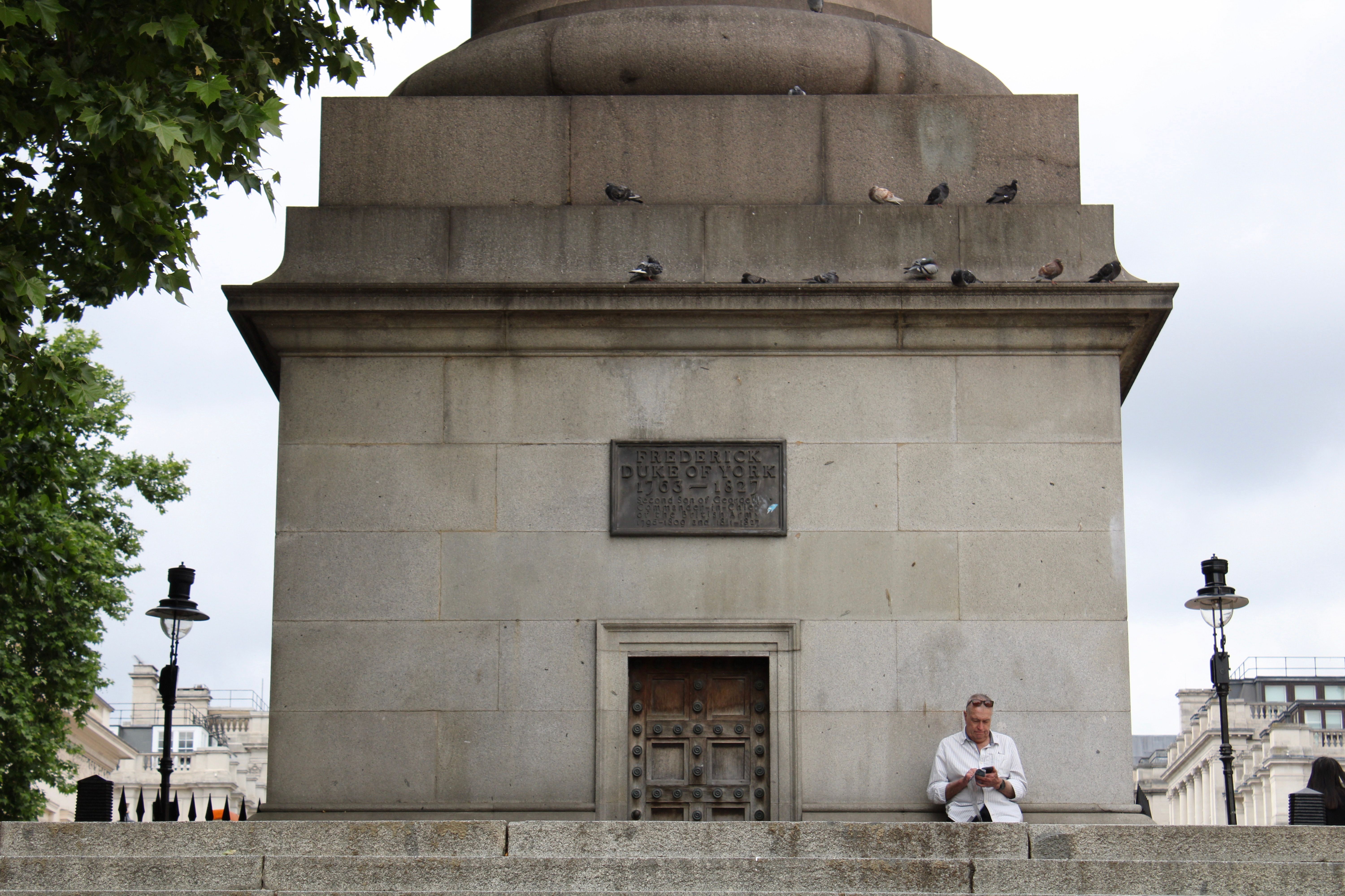 Man sitting by historical monument in city setting · Free Stock Photo