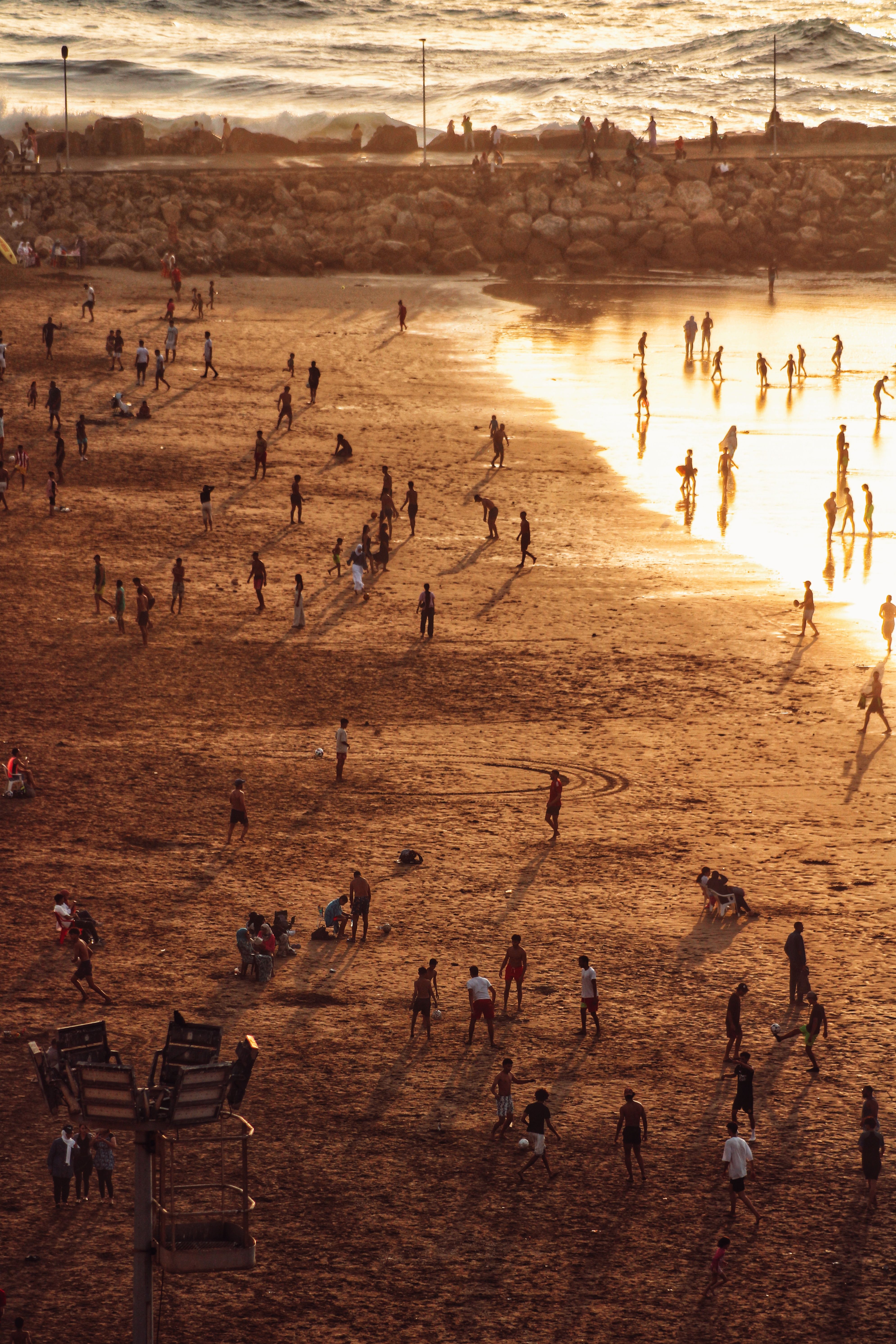 Sunset Beach Scene with People Playing and Relaxing · Free Stock Photo