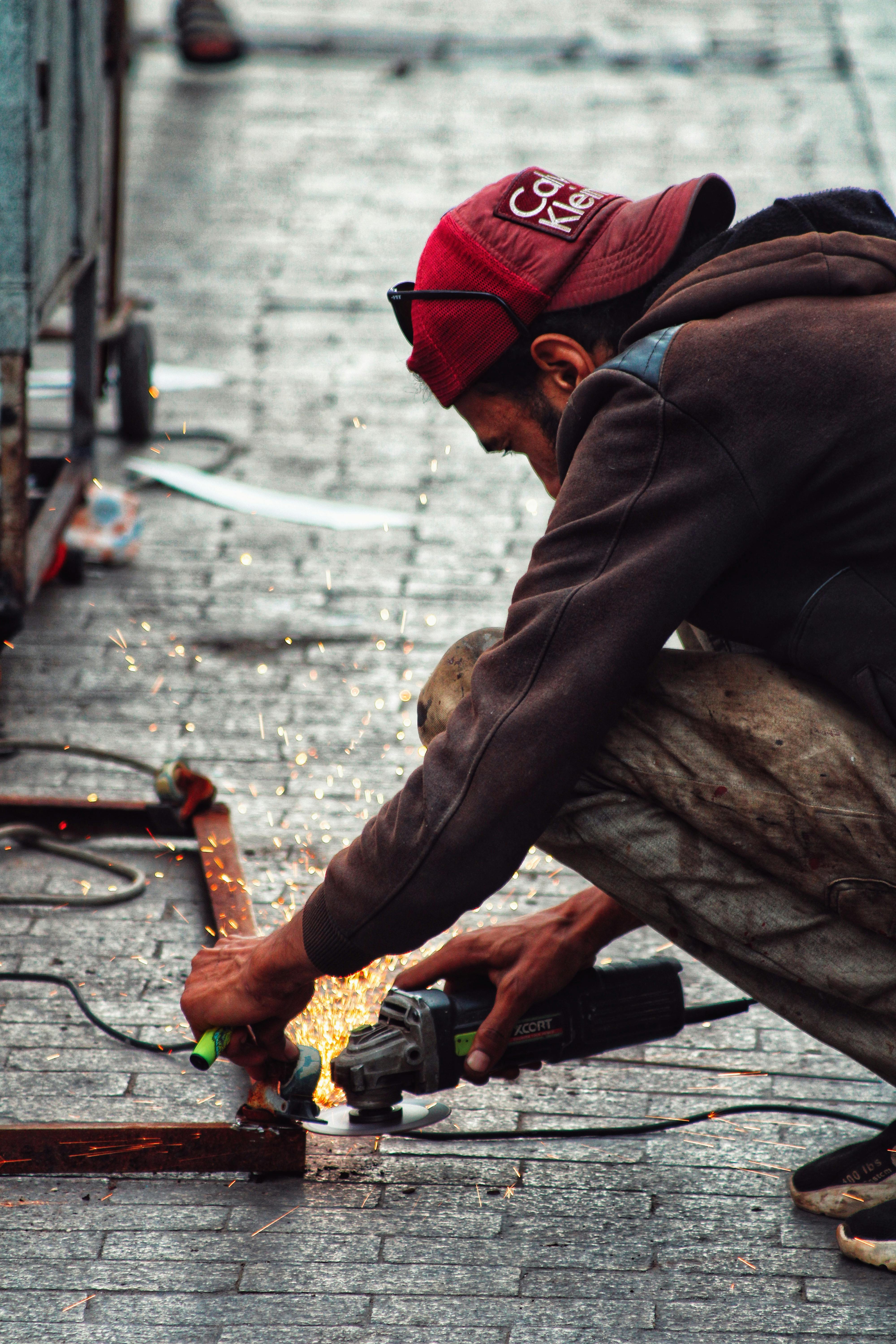 Man Using Angle Grinder to Cut Metal Outdoors · Free Stock Photo