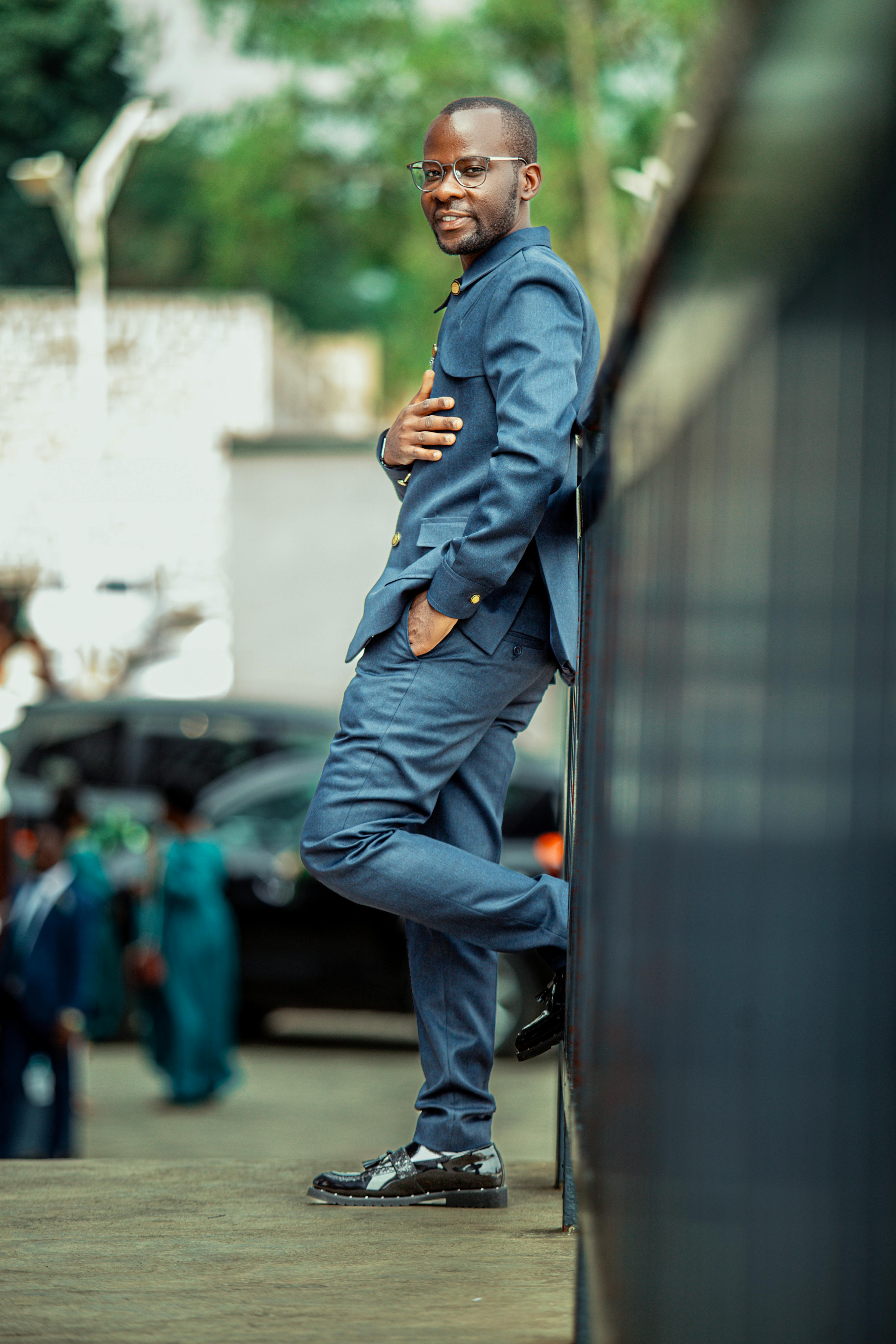 Stylish Man in a Blue Suit Leaning Against Rail · Free Stock Photo
