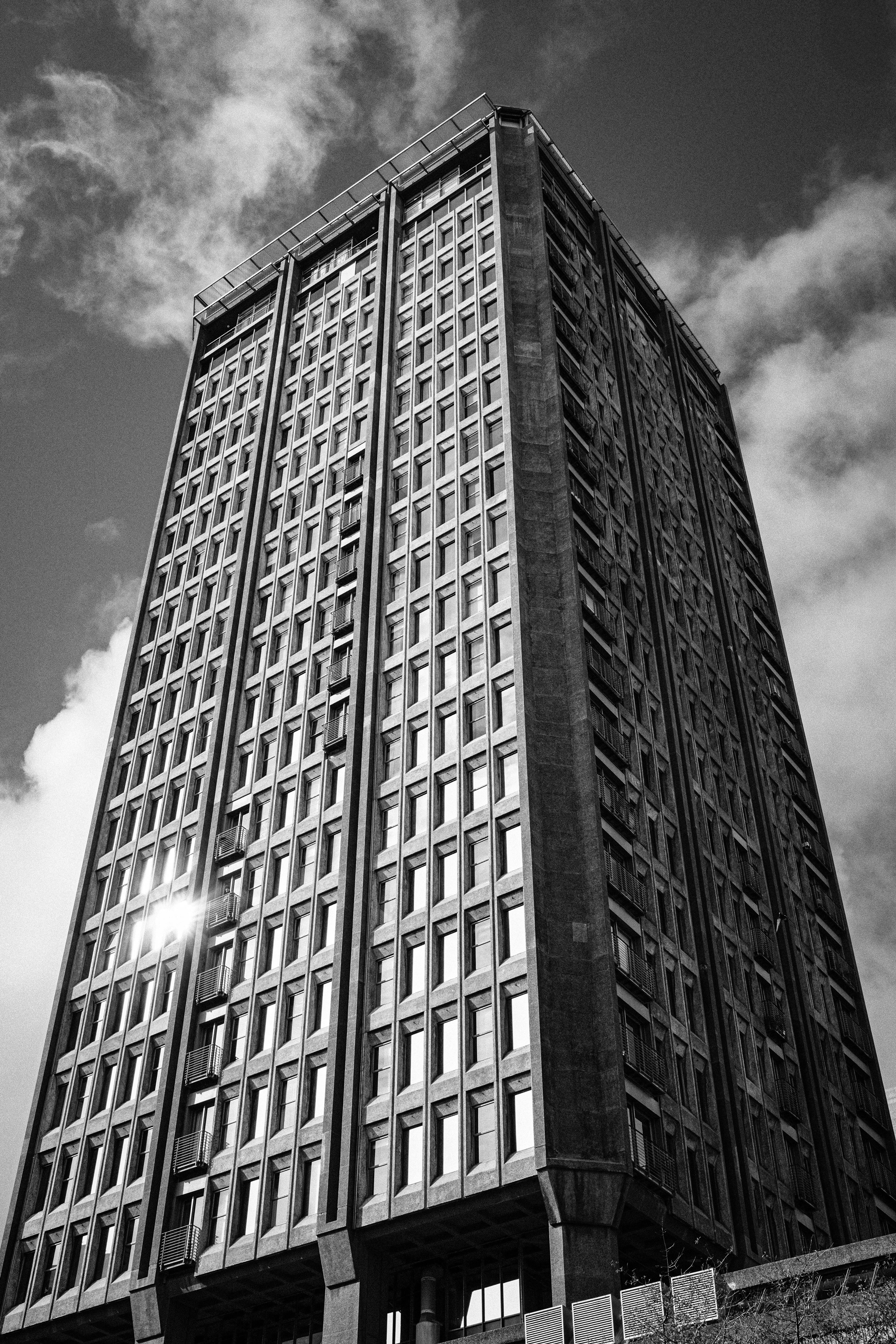 Tall Concrete Skyscraper Under Dramatic Clouds · Free Stock Photo