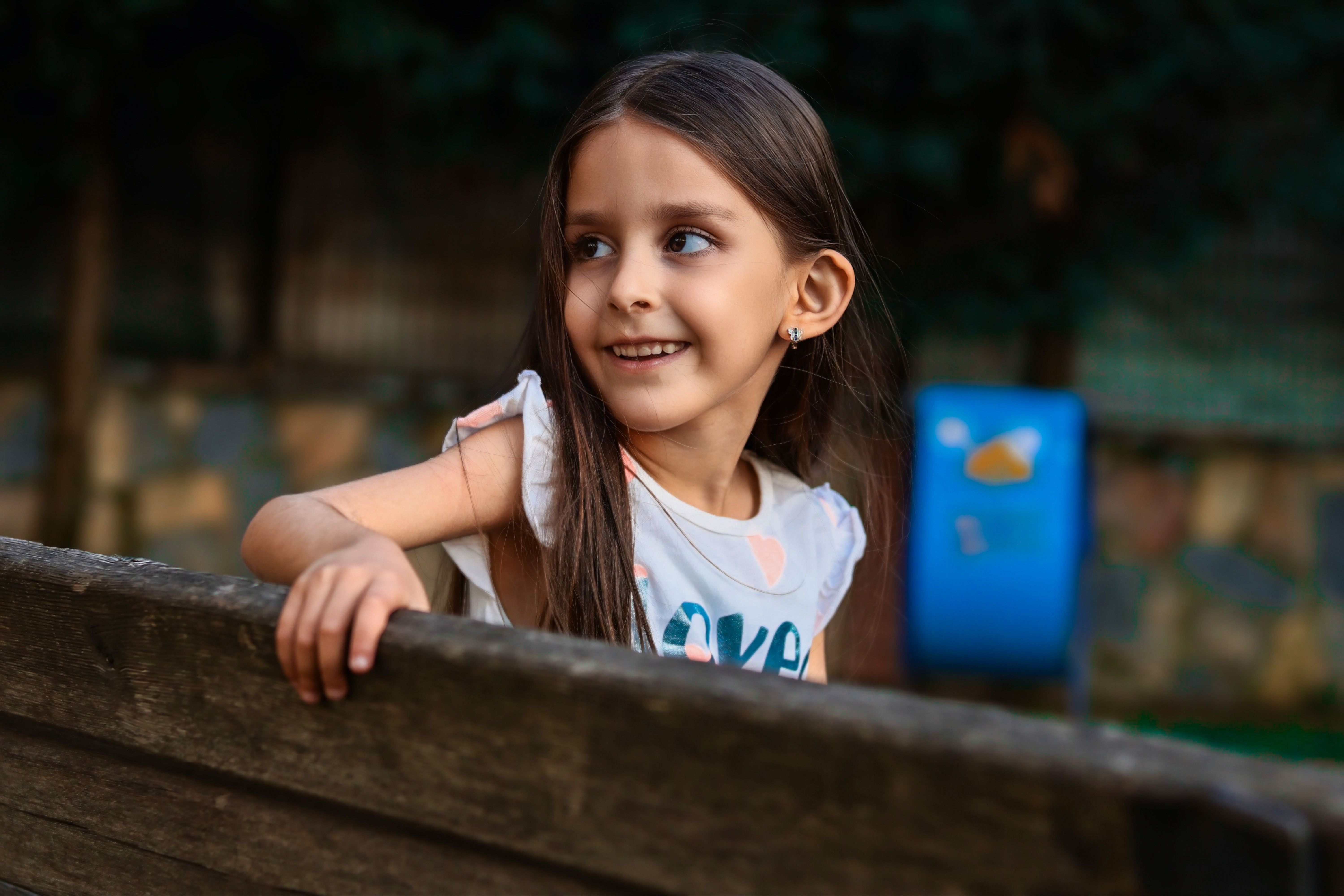 Smiling Girl Leaning on Park Bench Outdoors · Free Stock Photo