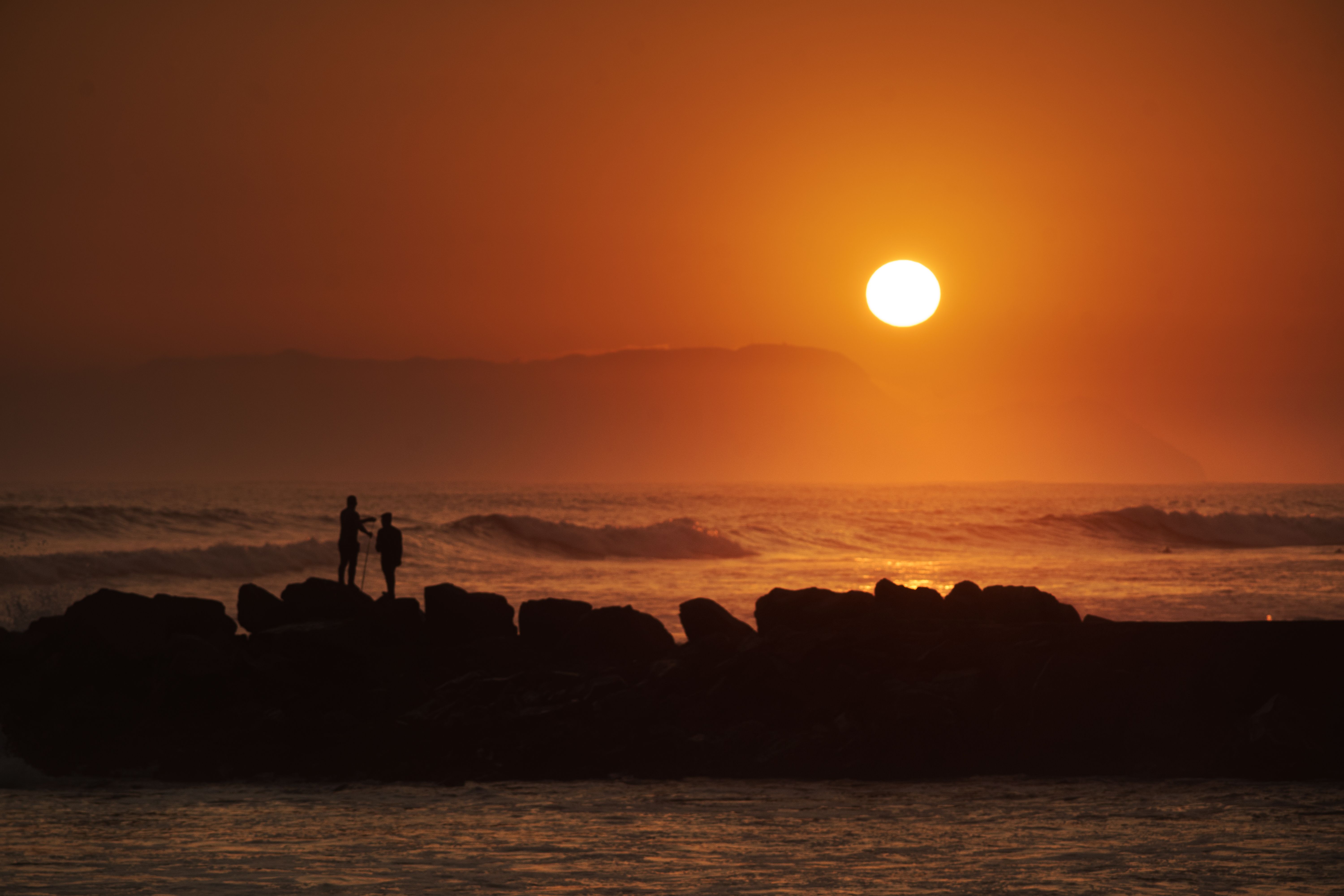 Stunning Sunset Over Lima Beach with Silhouettes · Free Stock Photo