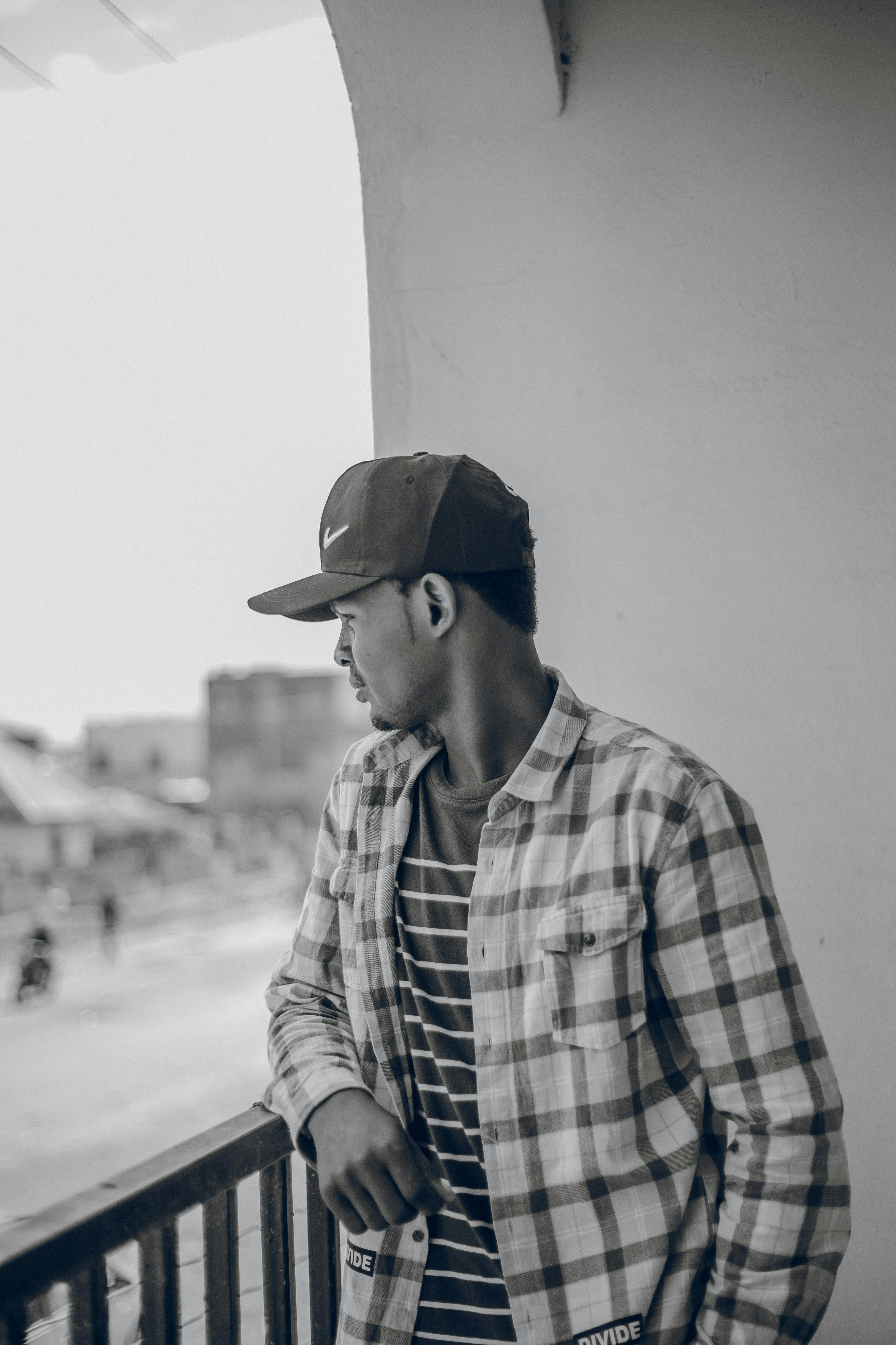 Young Man in Plaid Shirt Looking Out from Balcony · Free Stock Photo