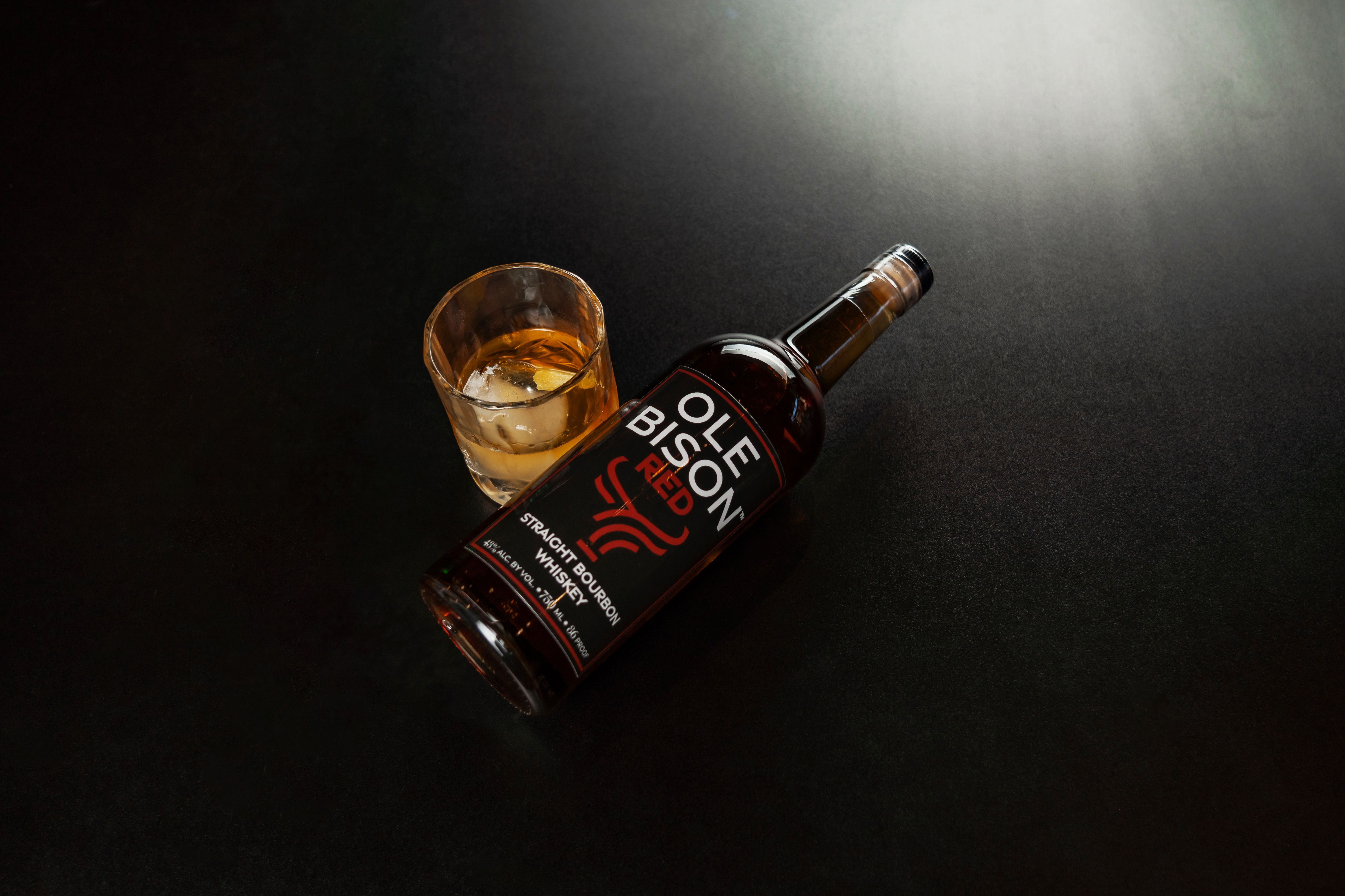 Ole Bison Whiskey Bottle with Glass on Dark Surface · Free Stock Photo