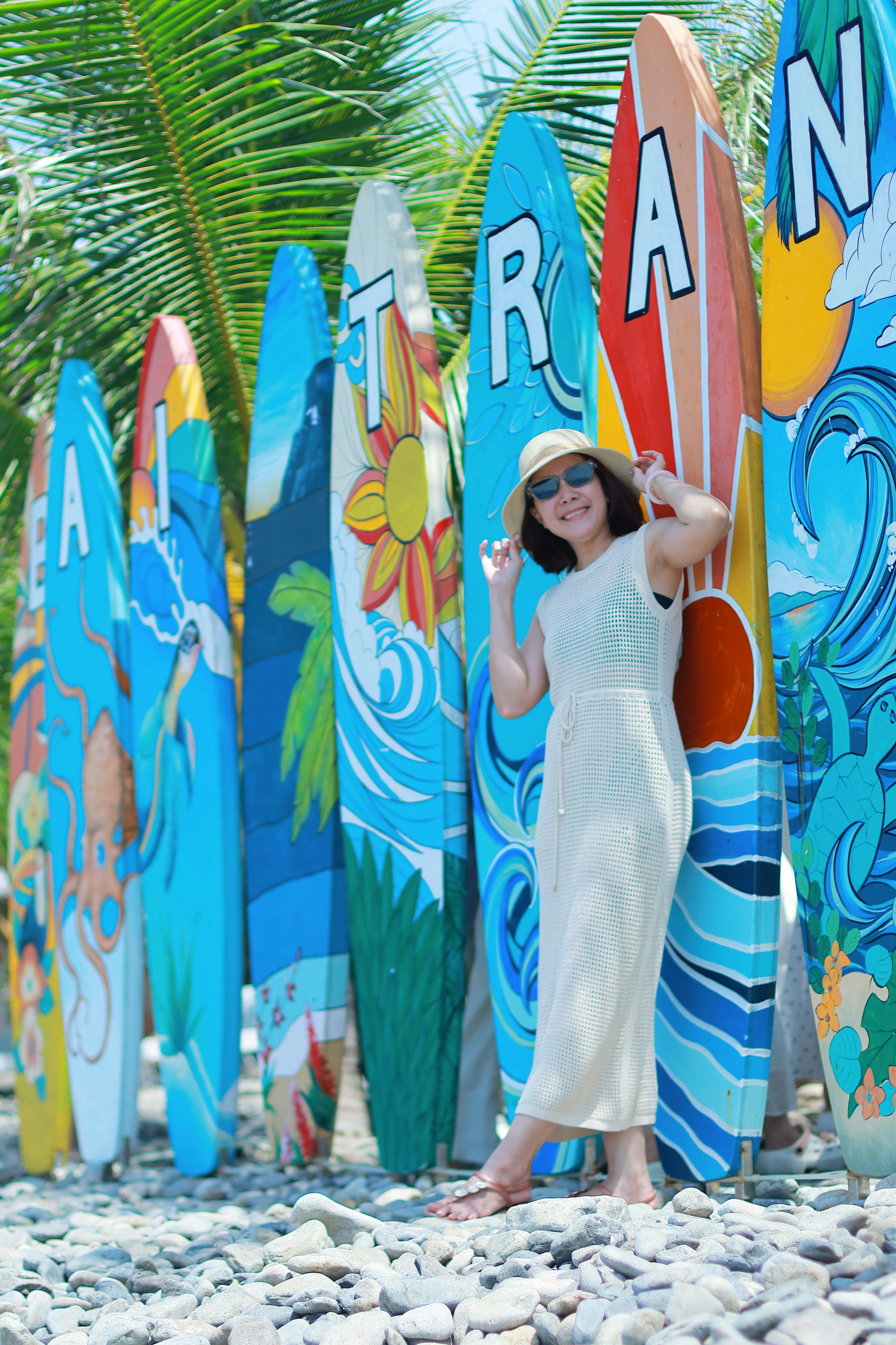 Woman Poses by Colorful Surfboards on Pebble Beach · Free Stock Photo