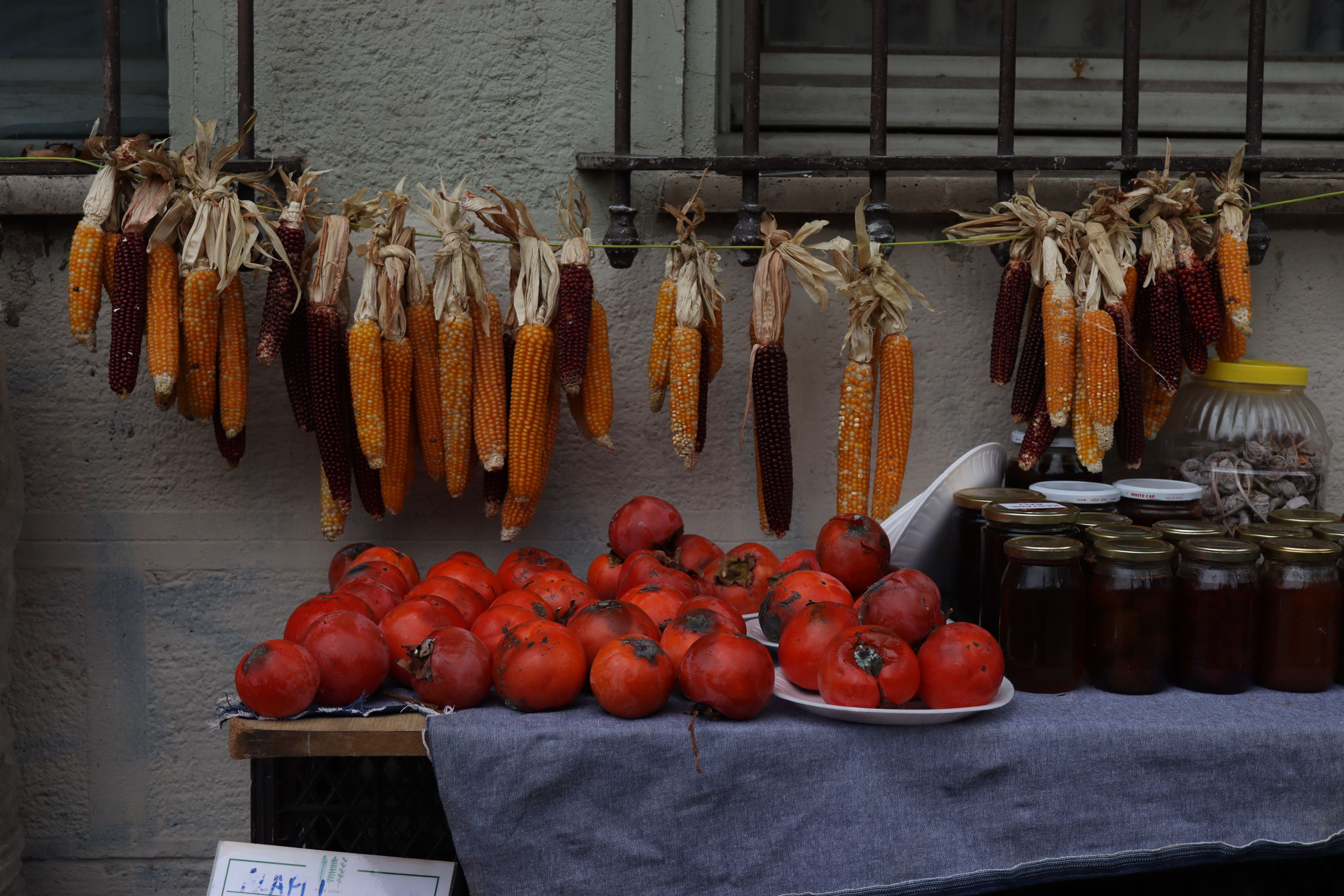 Rustic Display of Corn, Persimmons, and Jars at Market · Free Stock Photo