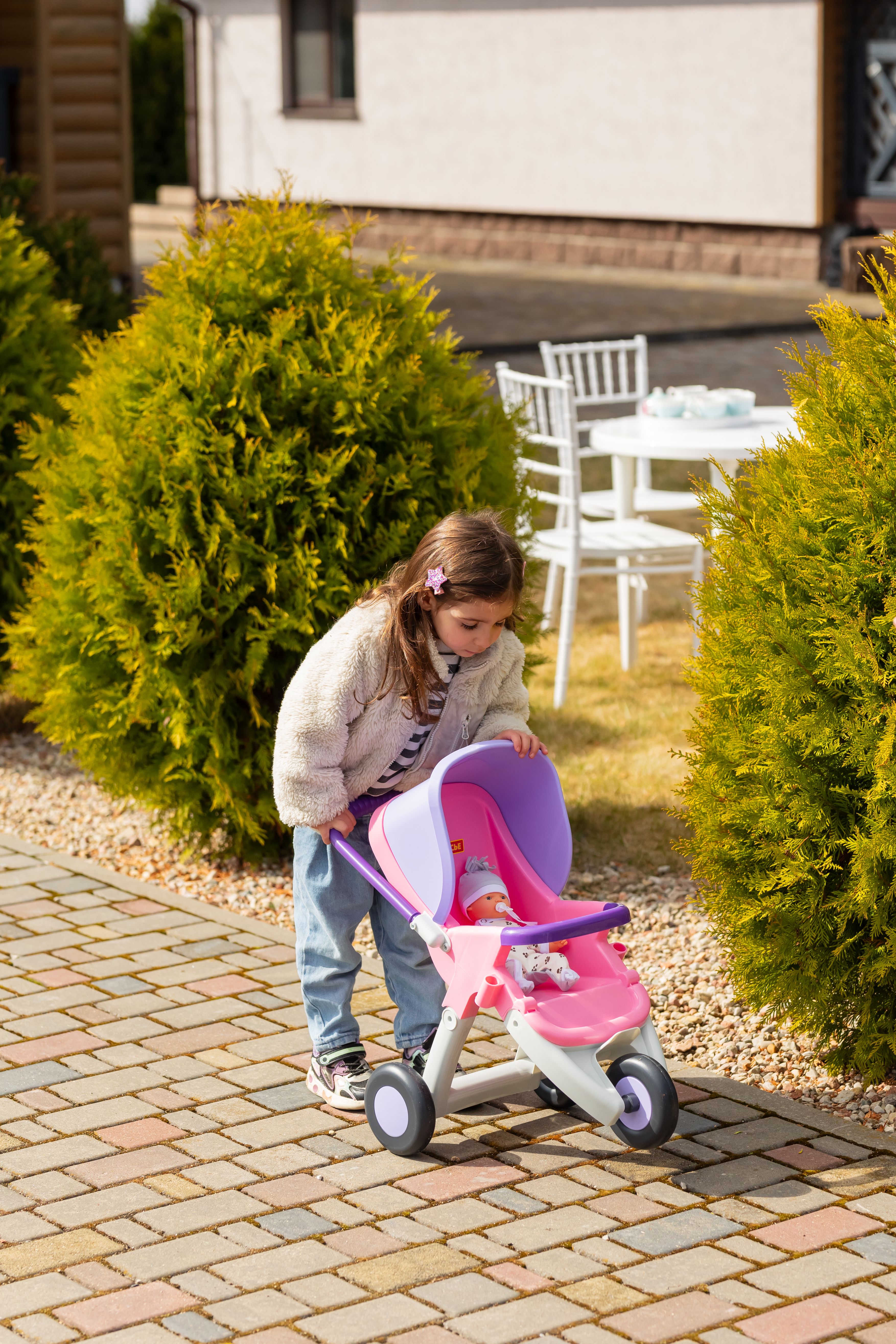 Young Girl Playing Outdoors with Toy Stroller · Free Stock Photo