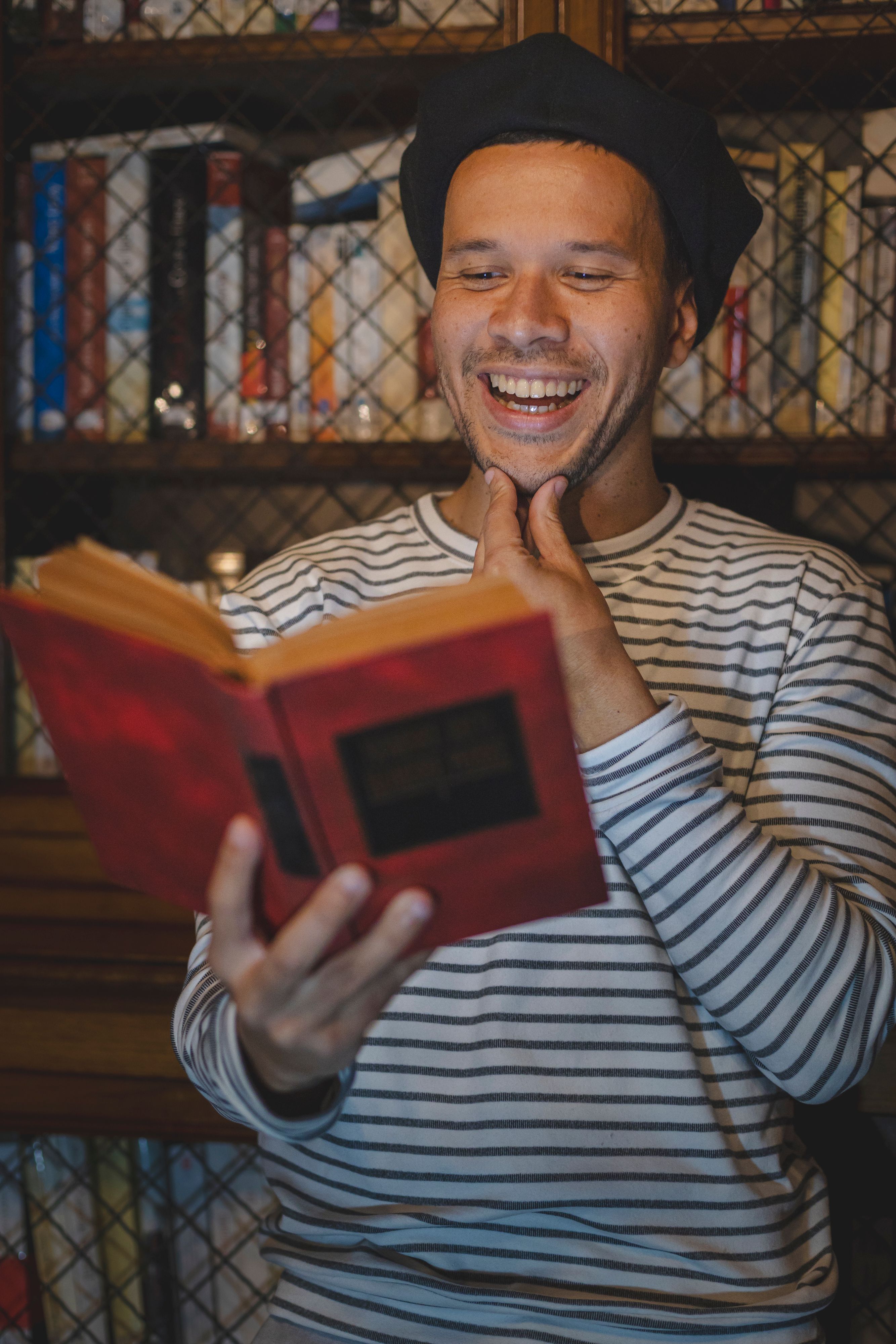 Smiling Man Enjoying a Book in Cozy Library · Free Stock Photo